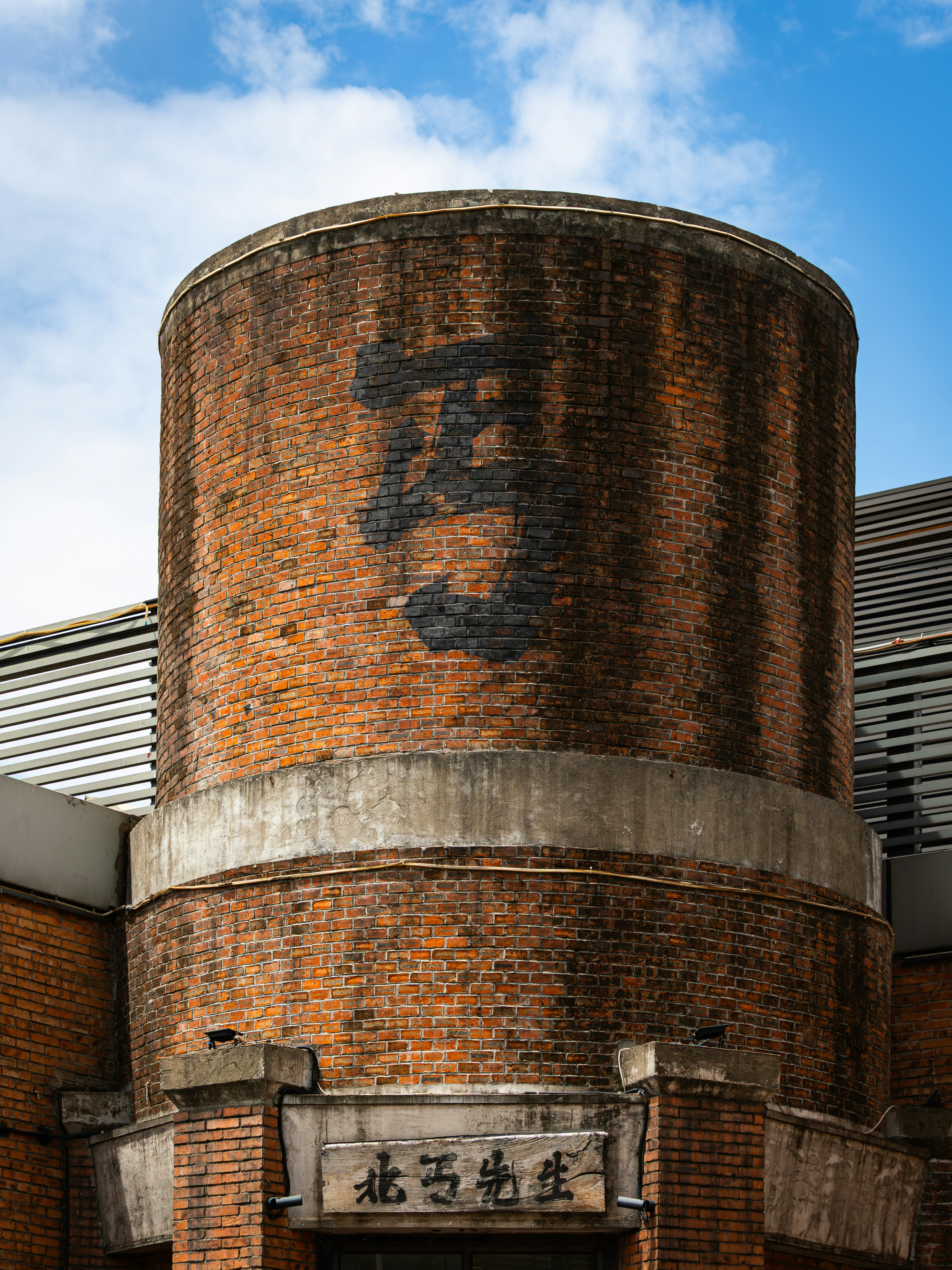 Cylindrical brick building with black character under a blue sky.