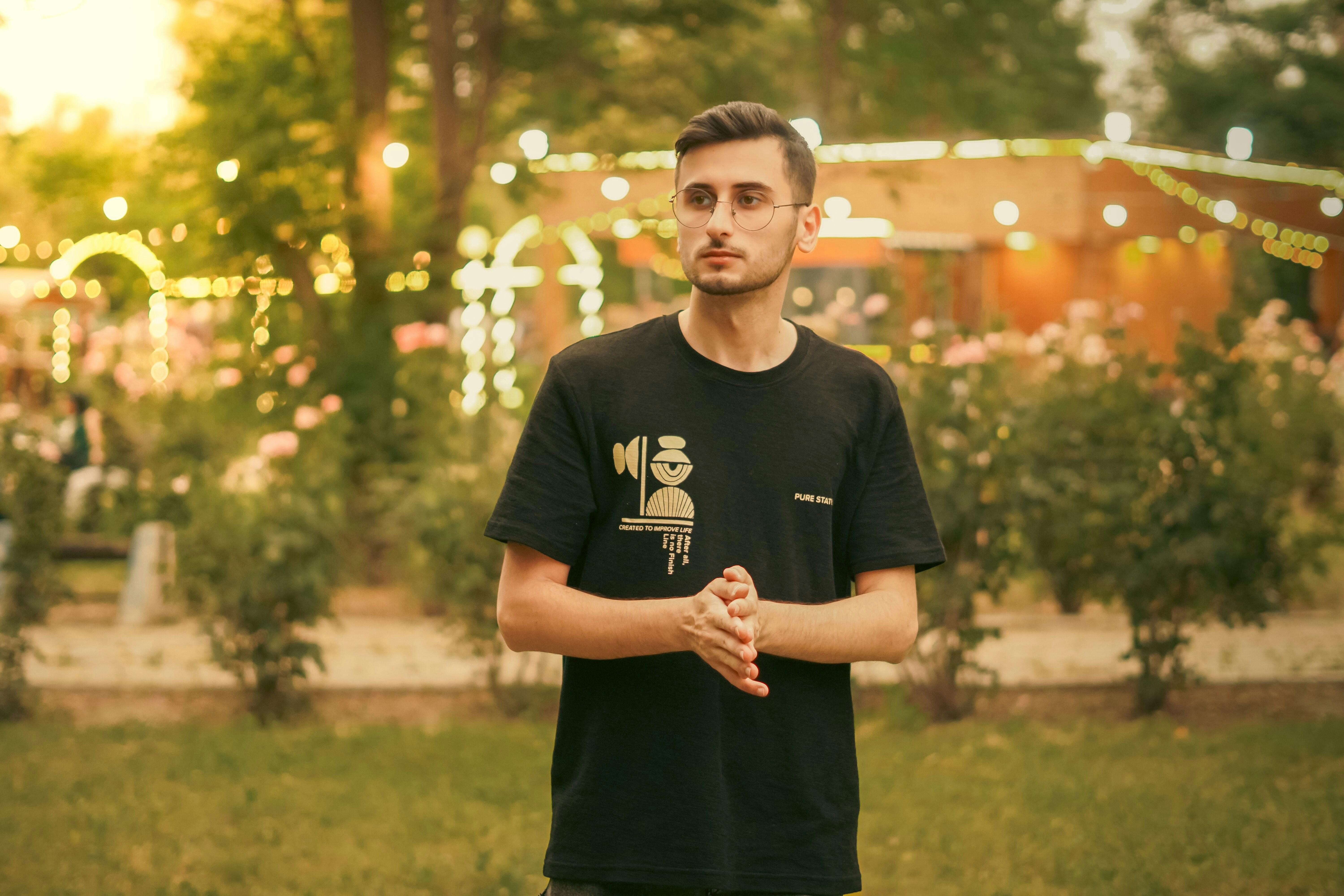 Portrait under string lights: a calm figure in a garden dusk