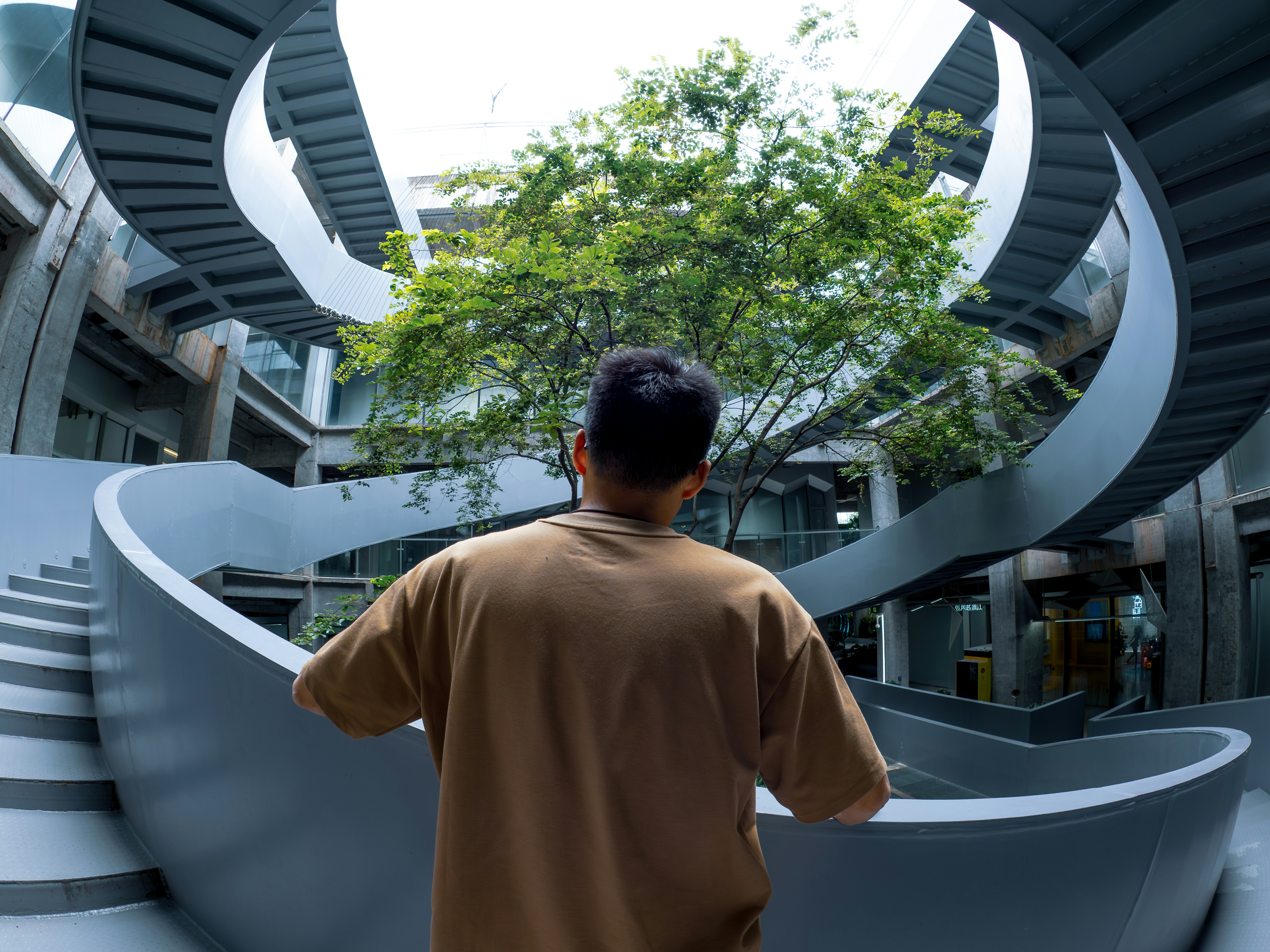 Backstopped by Spiral Architecture, a Traveler in Tawny Shirt Gazes Toward an Infinite Staircase