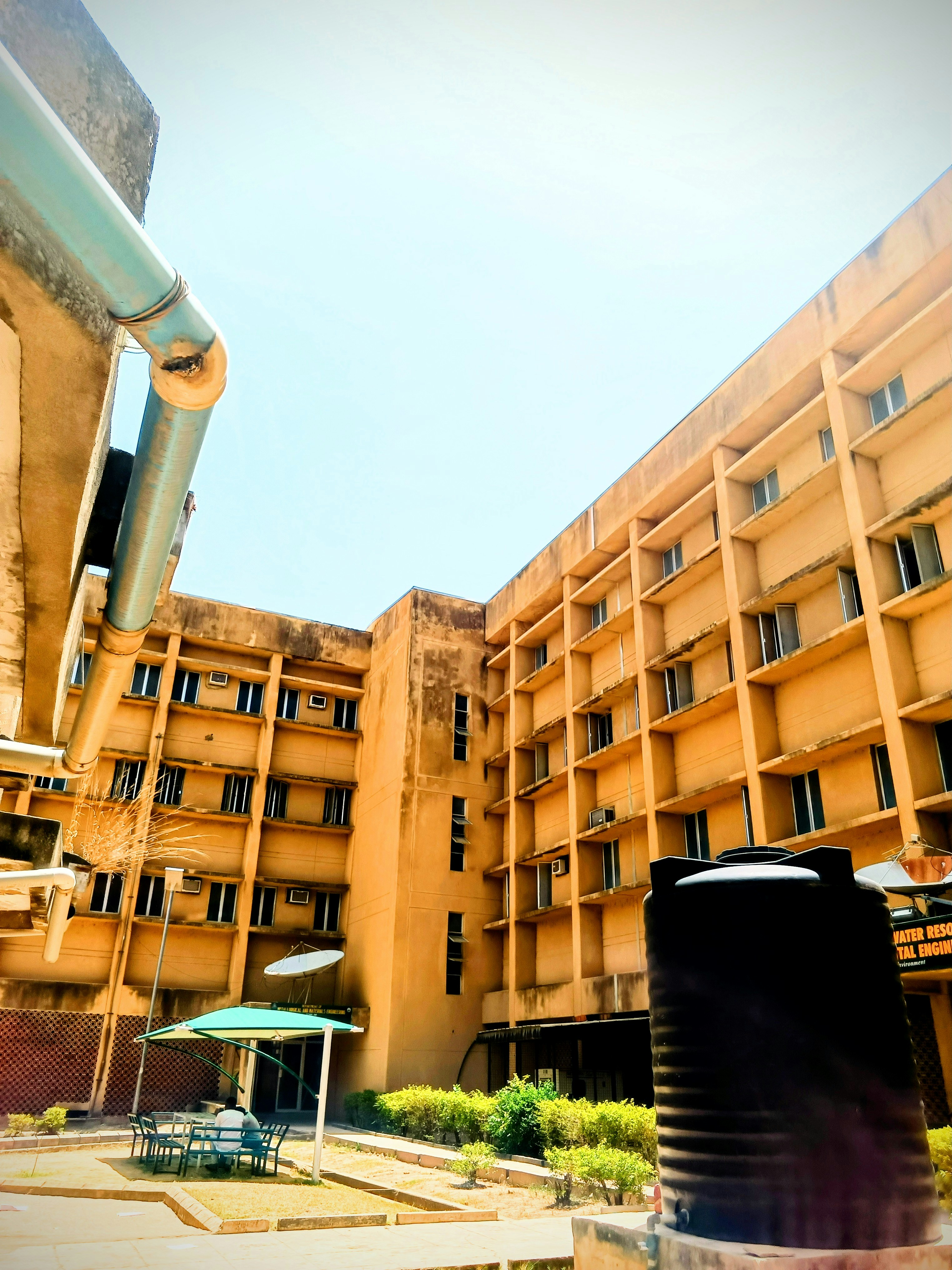 Multi-story ochre building with a courtyard and clear blue sky.