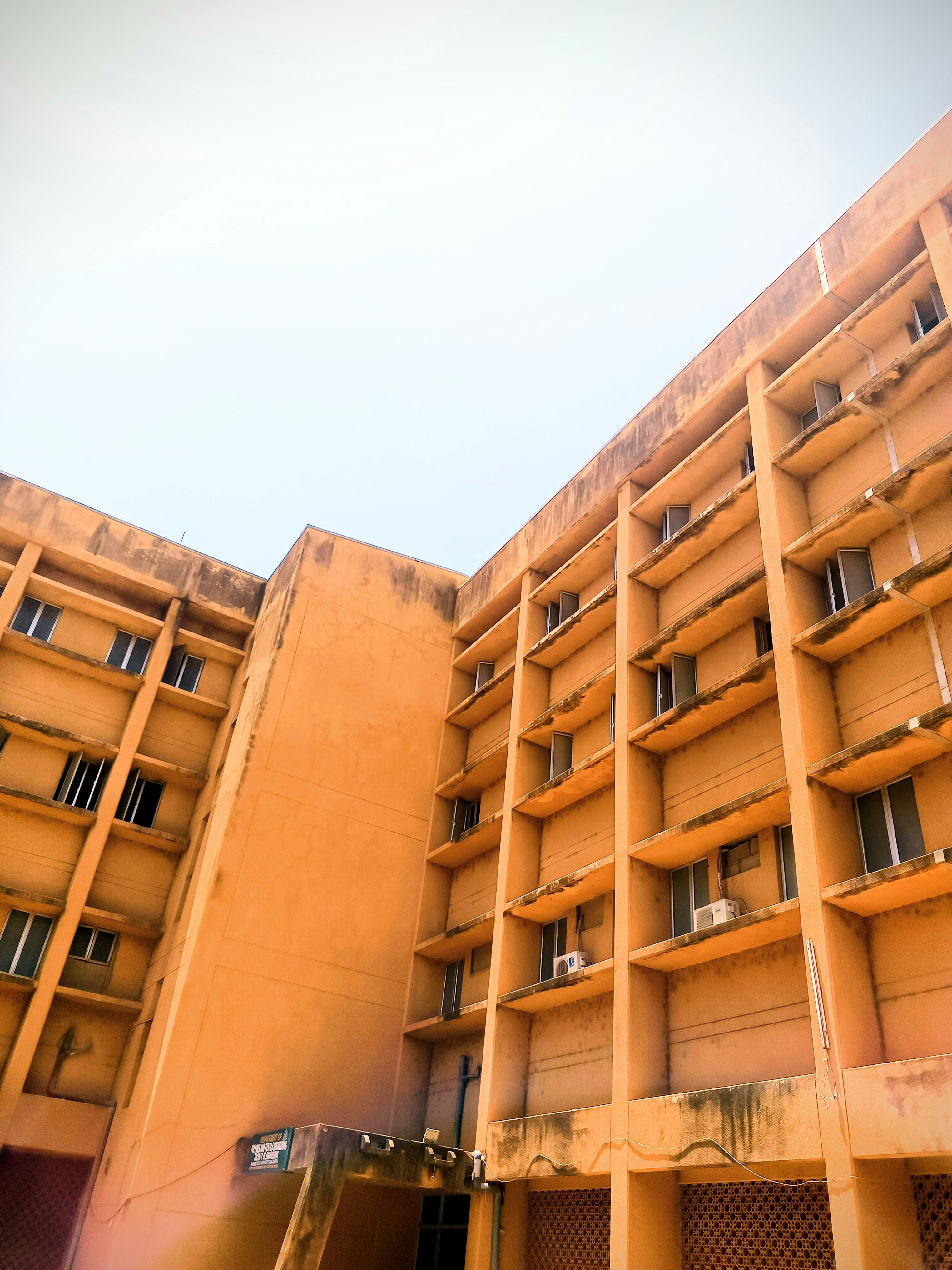 Large orange building with many windows under a bright sky.
