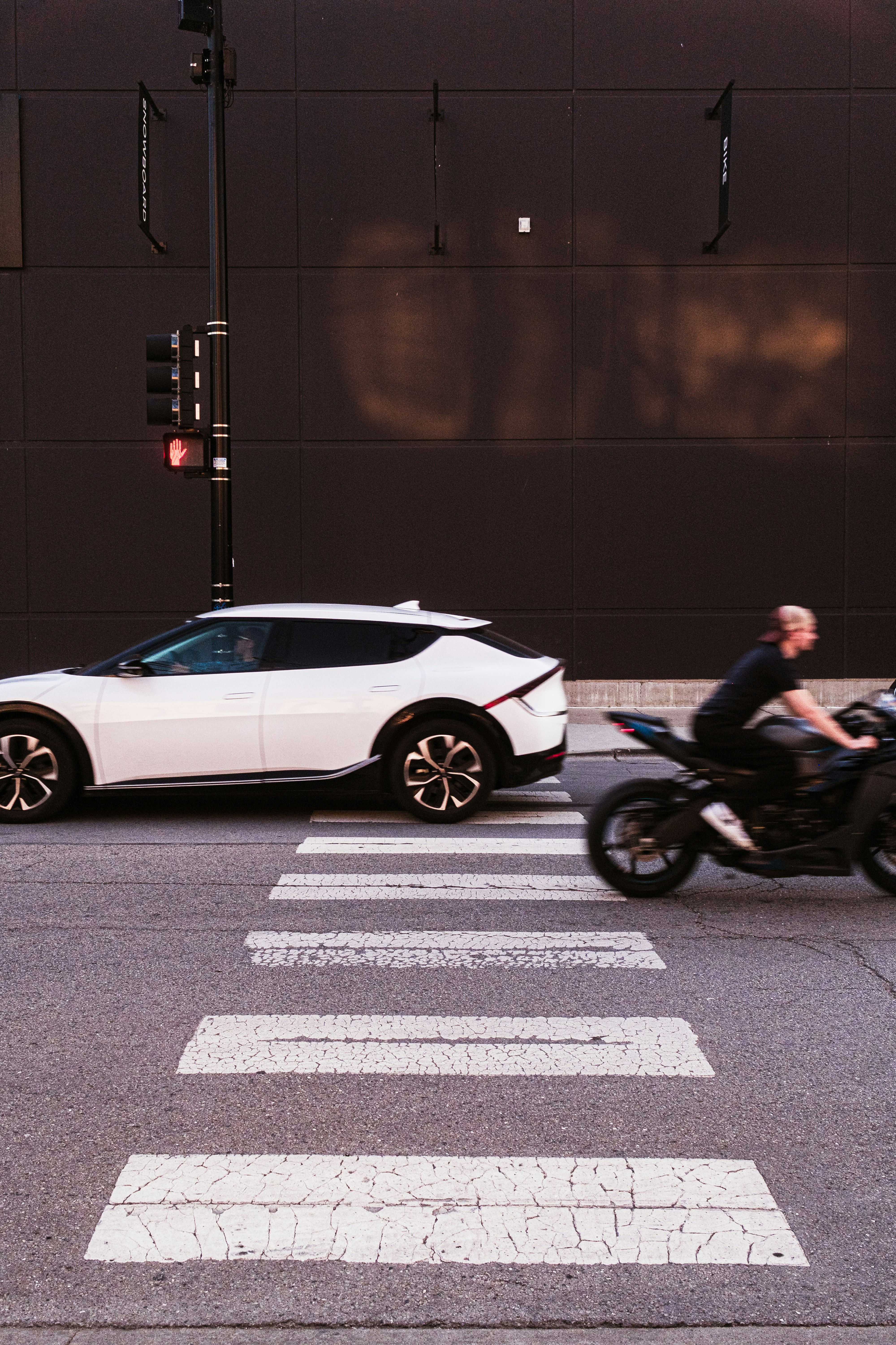 Crosswalk Pulse: White Car, Blurred Motorcycle, City Fragments