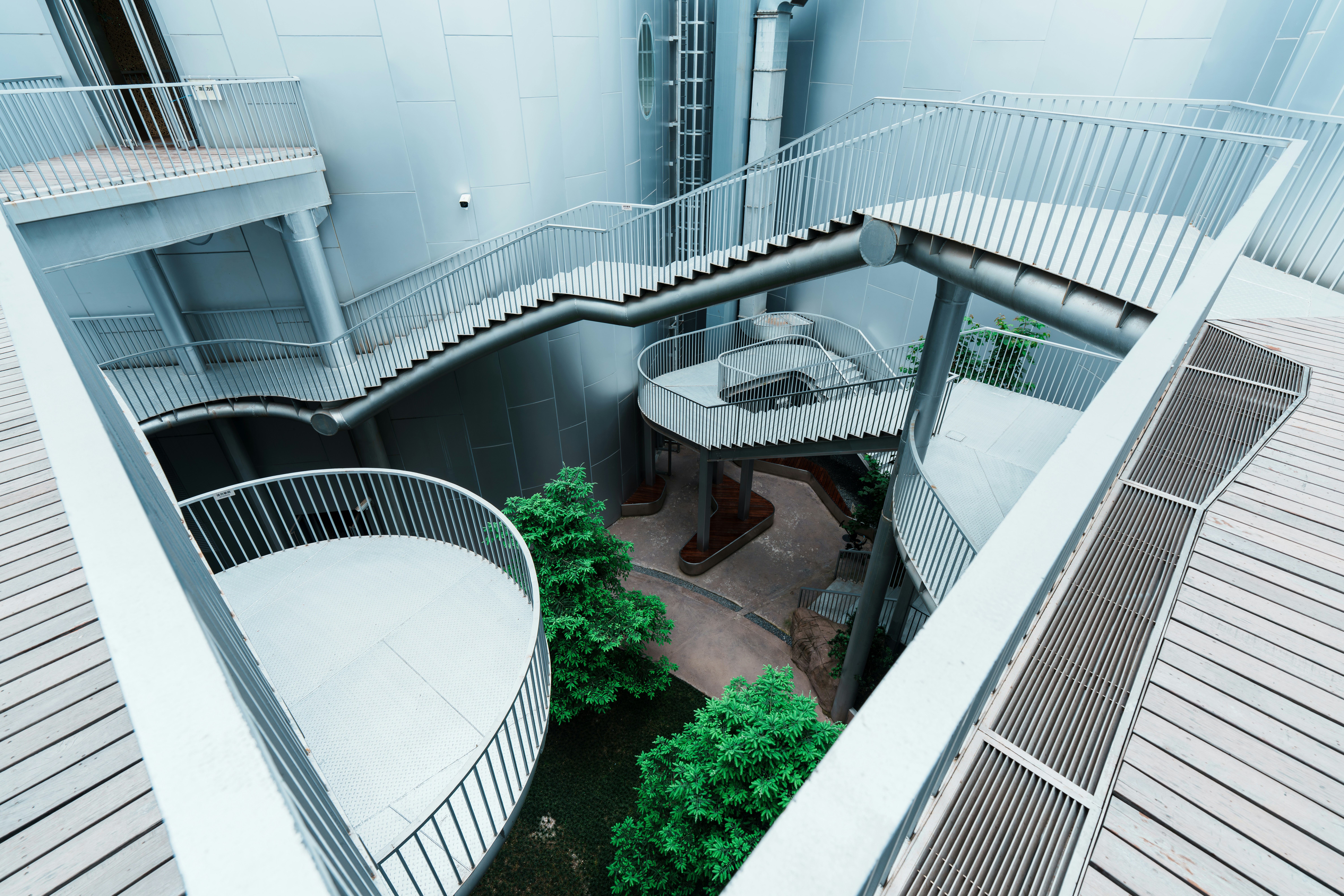 Vertical Maze: Aerial View of a Modern Atrium with Circular Staircases and Verdant Focal Point