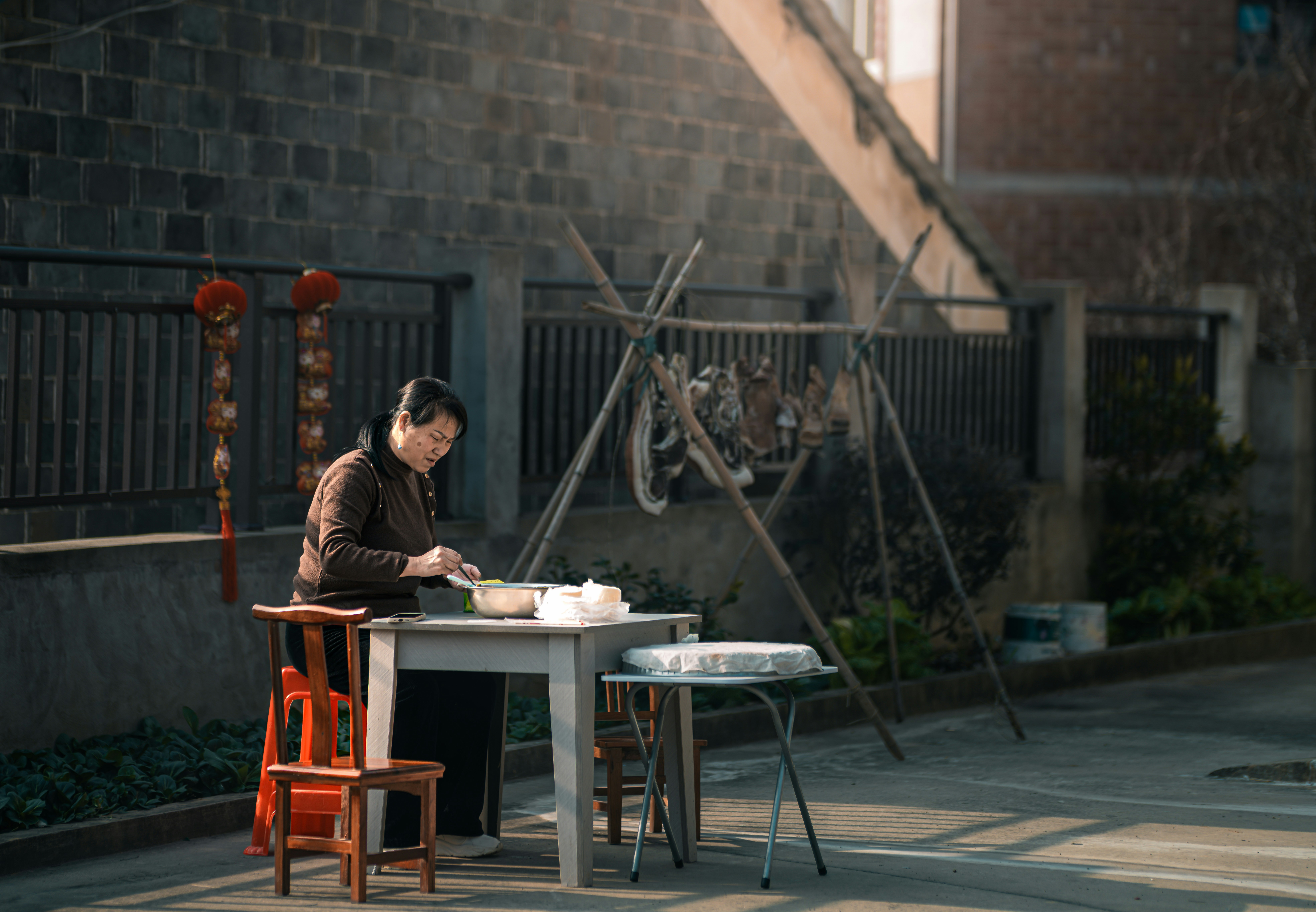 A woman prepares food at an outdoor table.