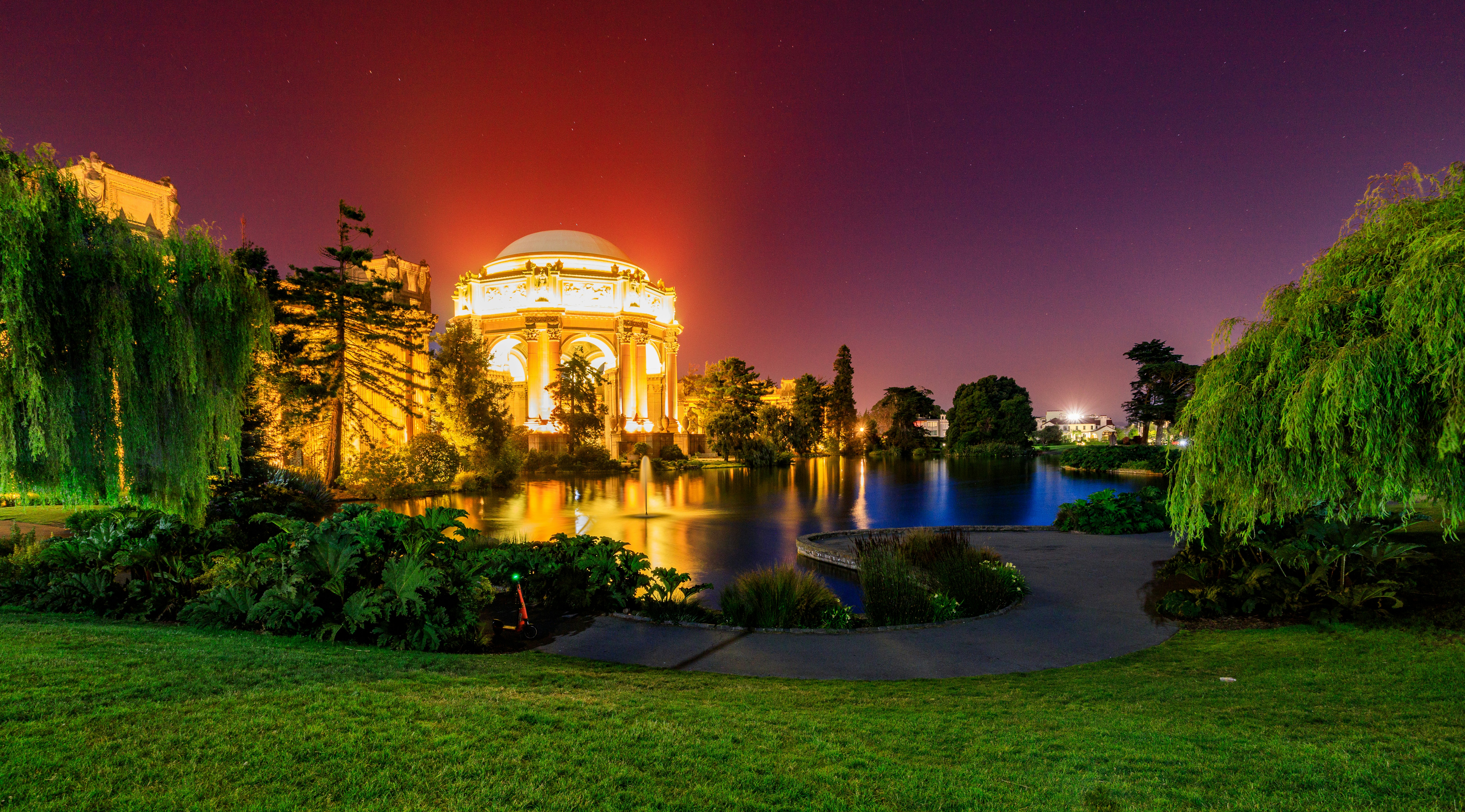 Illuminated palace of fine arts reflected in water at night.