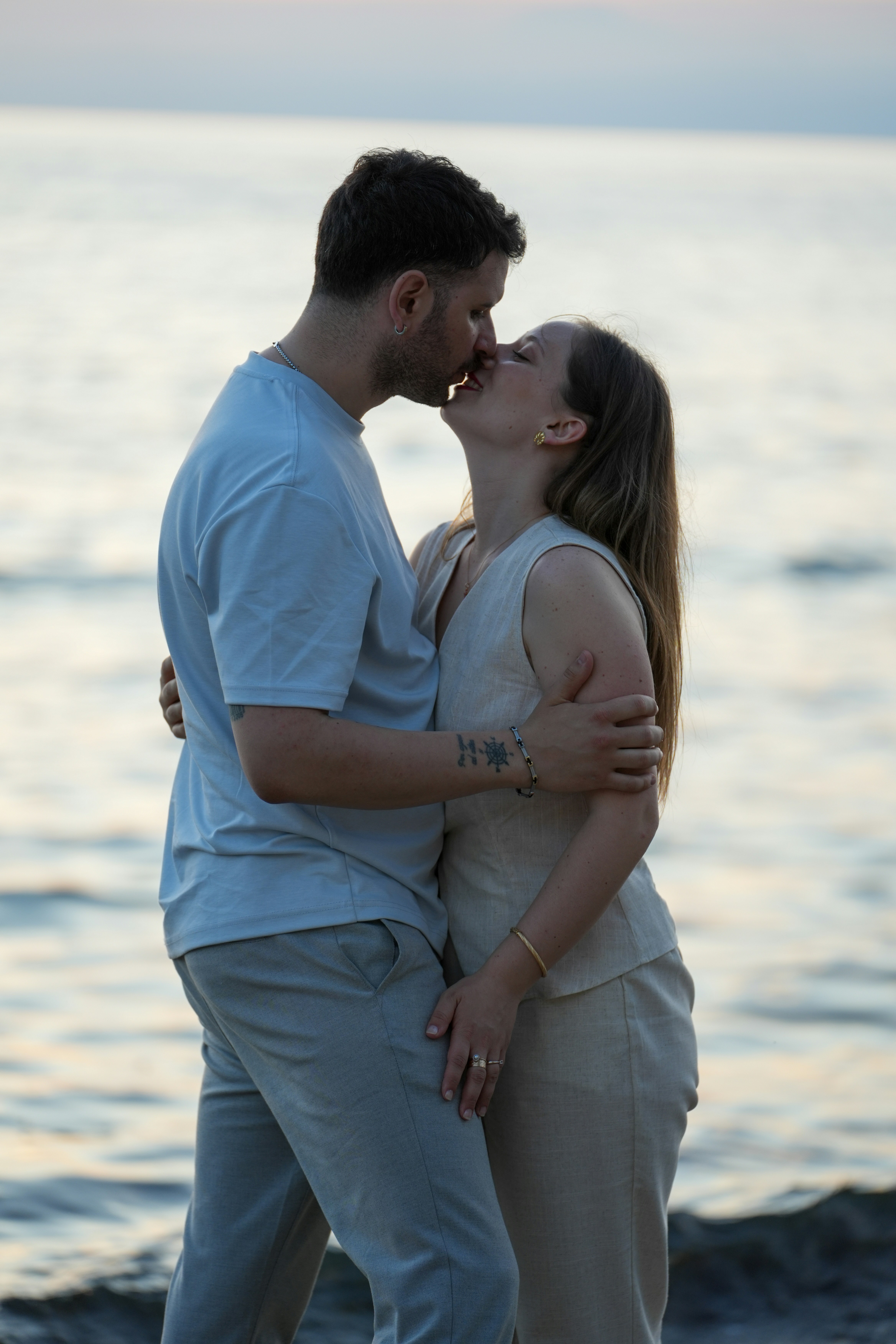 Kiss at Dusk: Lovers Embrace by the Quiet Sea