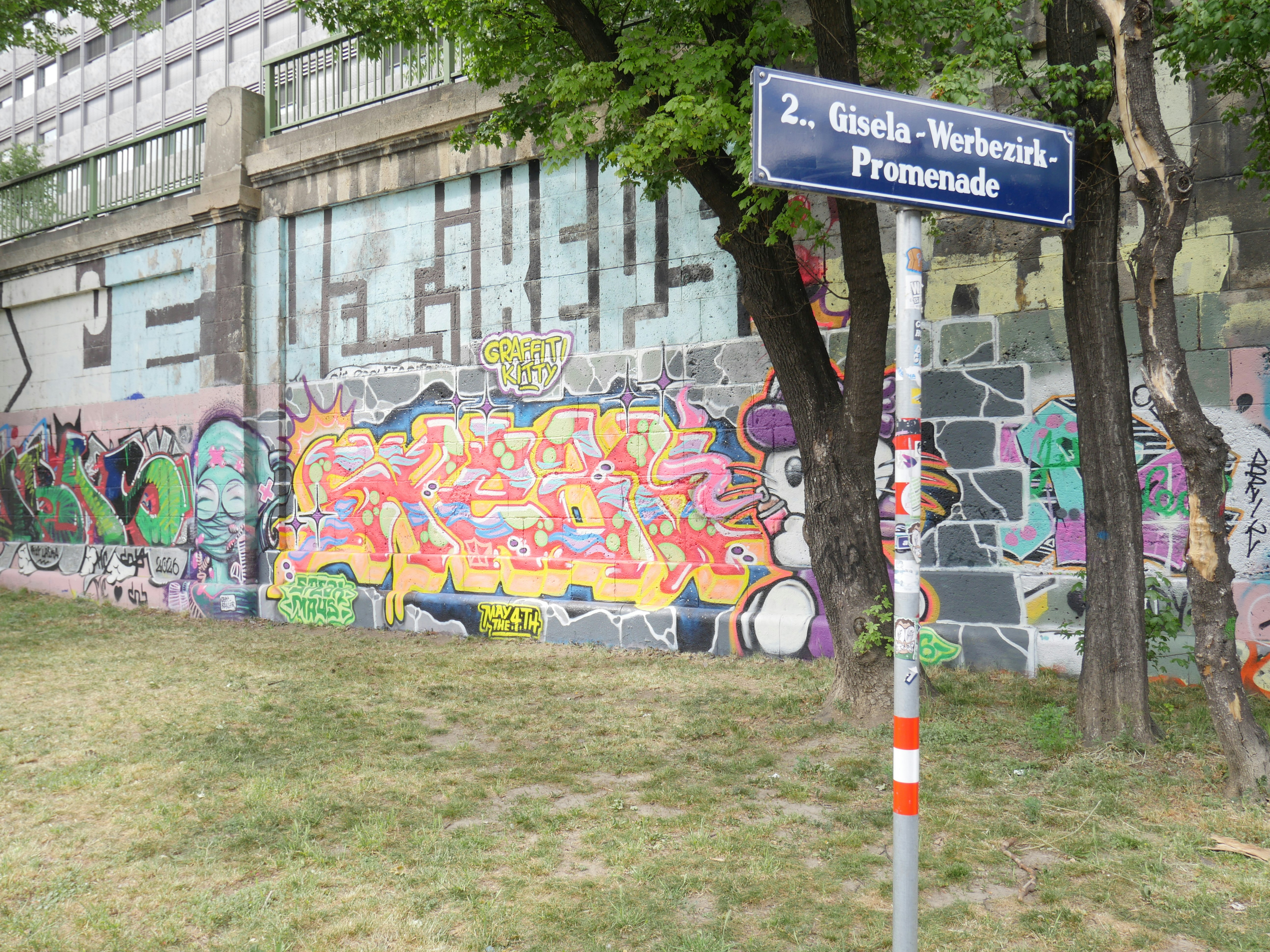 Colorful Graffiti Wall Framed by Street Sign and Trees
