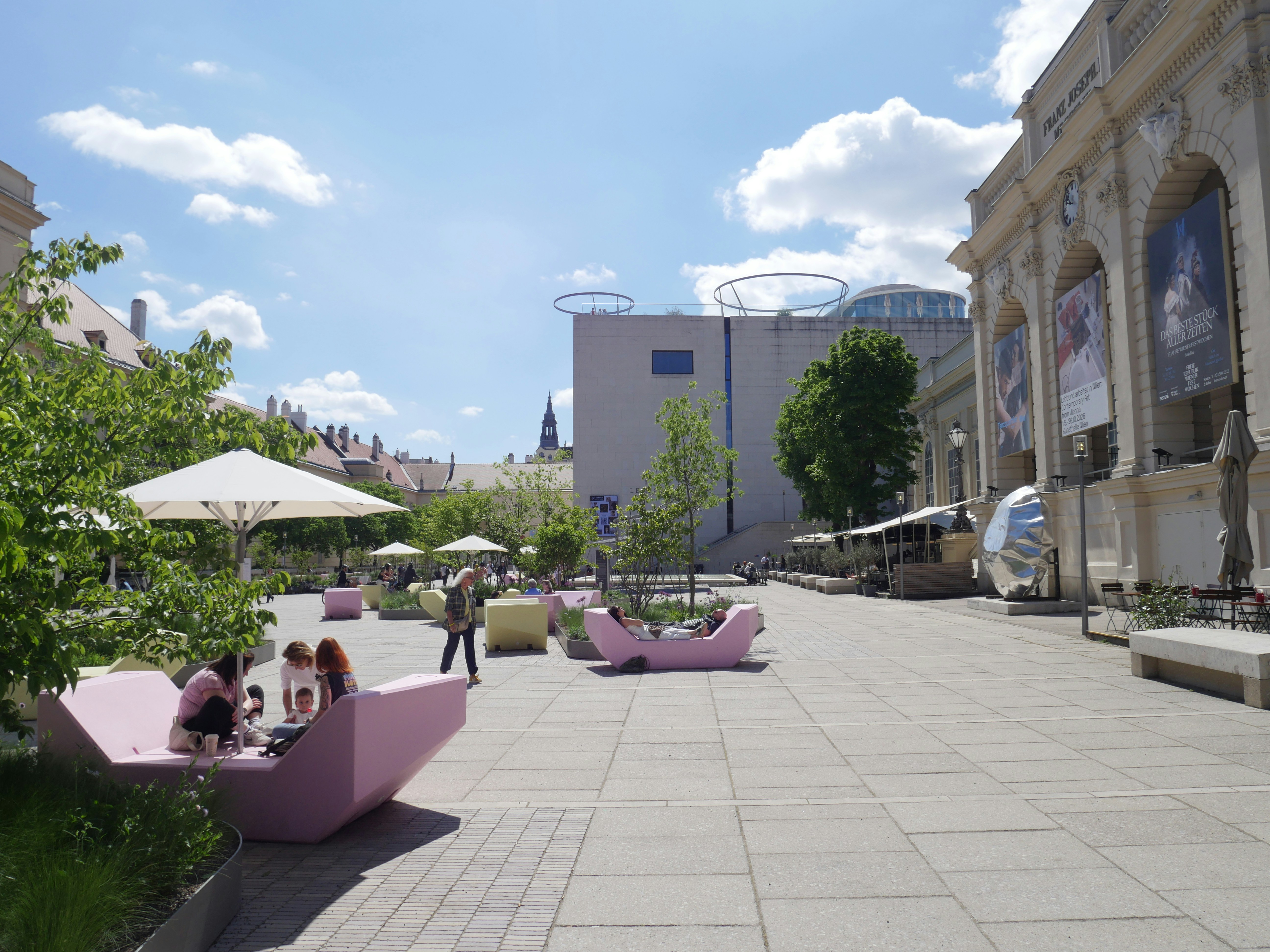 Sunlit Plaza: Pink Lounge Chairs and Classical Architecture