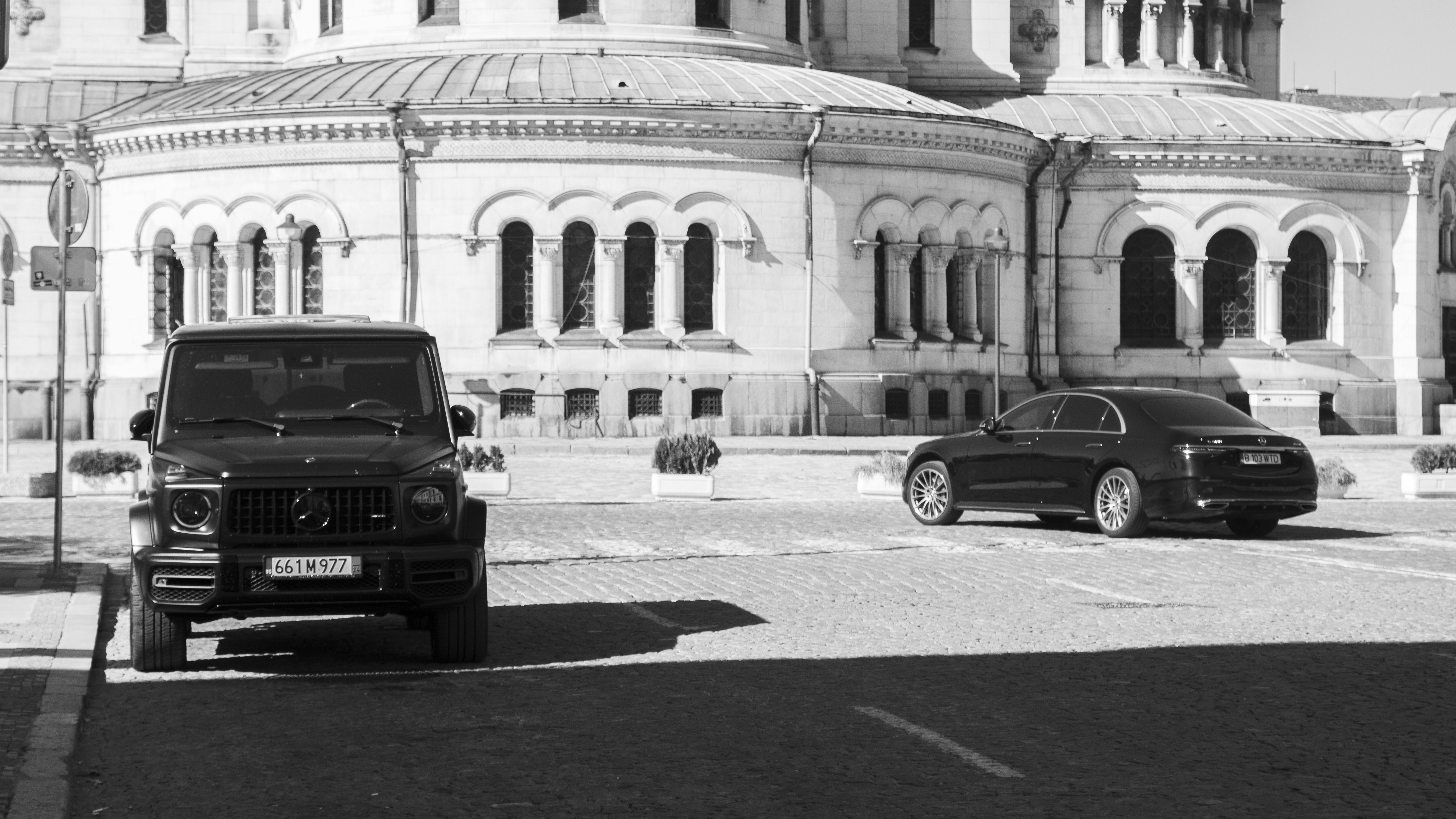 Vehicles Quietly Guard a Historic Facade in Sunlit Street