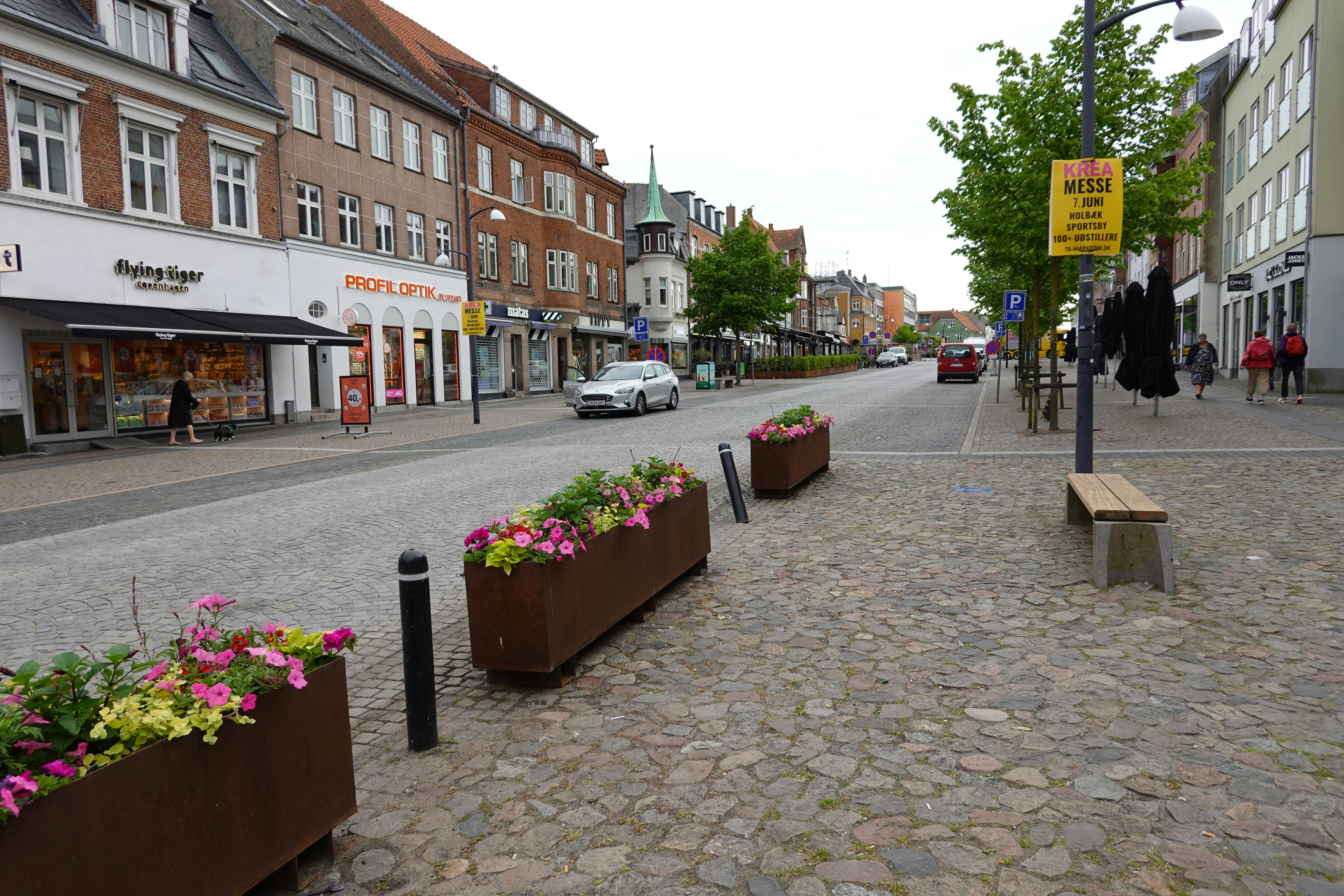 Cobblestone Avenue: Flower Planters and Shops Framing a Quiet Town Street