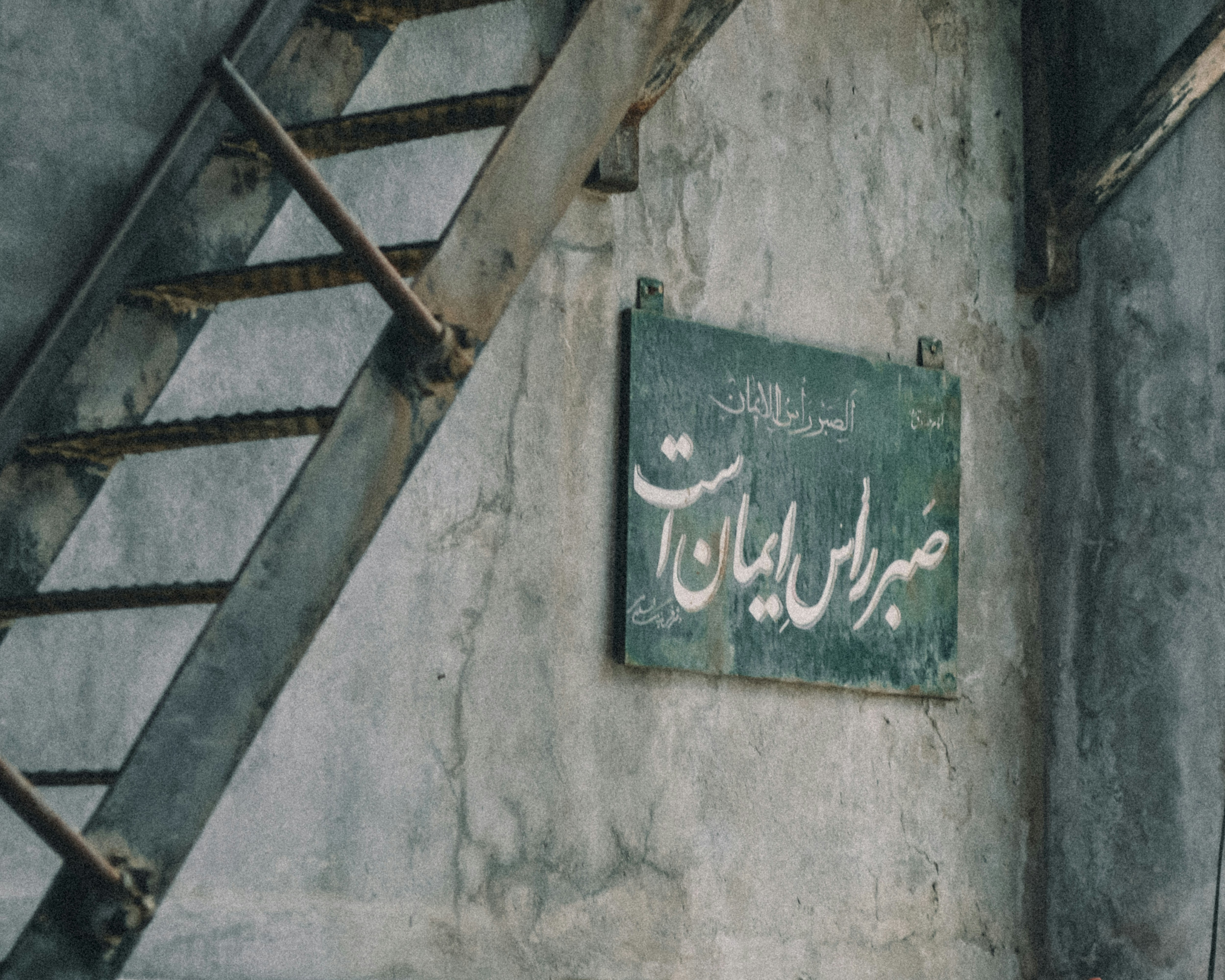 Weathered Green Sign on Concrete Wall beside Rustic Staircase