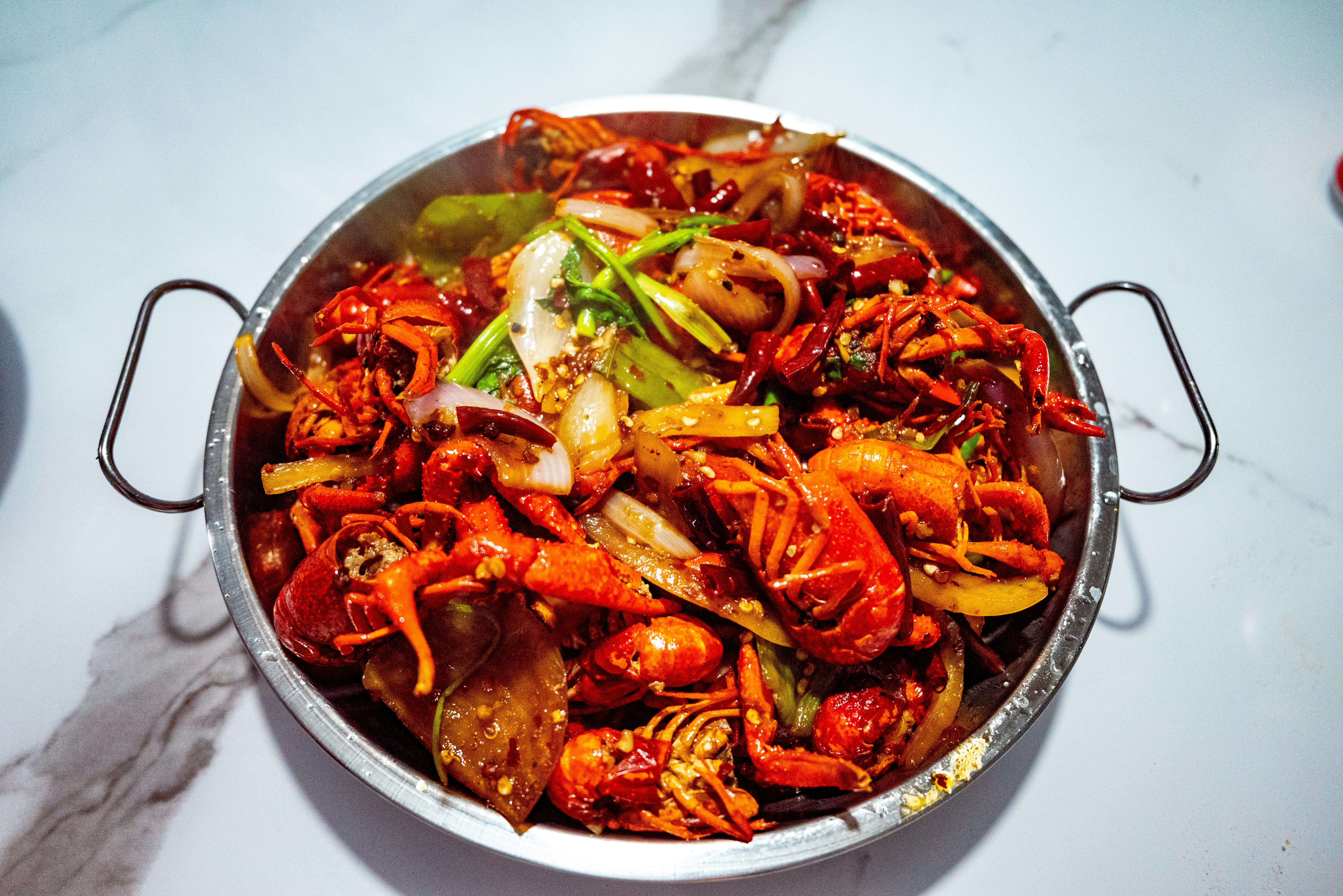 A metal pot filled with spicy crawfish and vegetables.