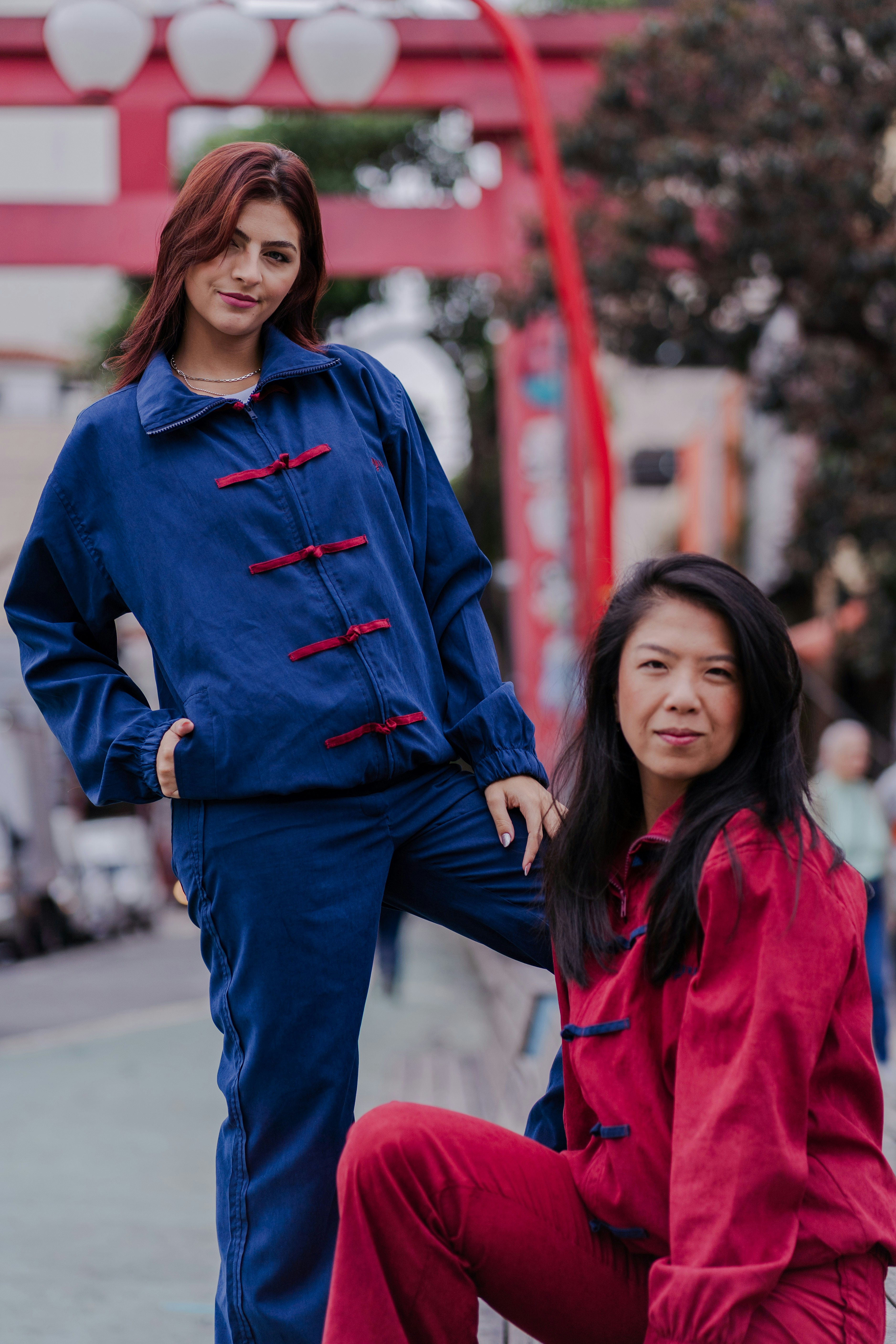 Twin poses in color: two women in bold red and blue uniforms framing an urban setting