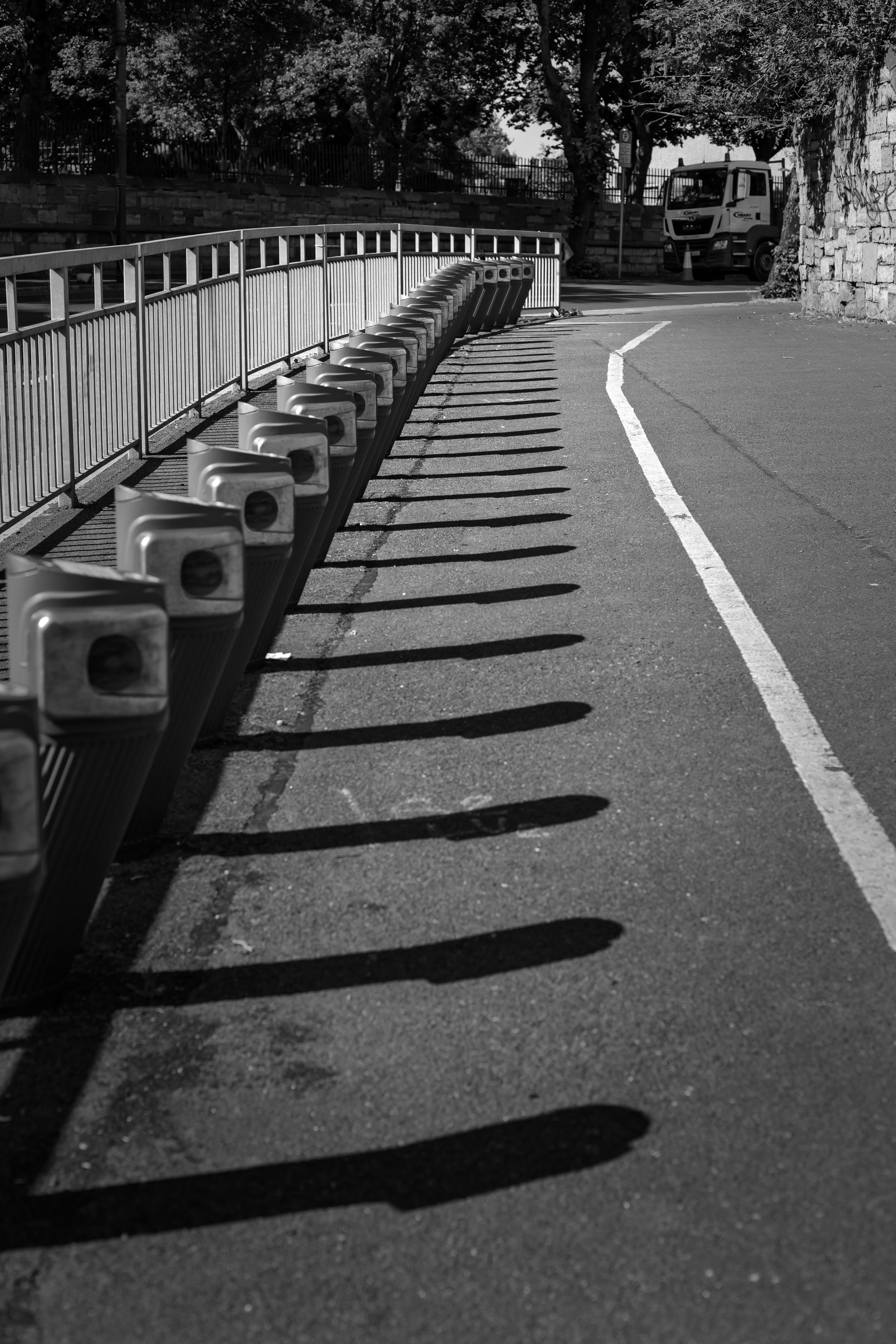 Row of Street Trash Receptacles Cast Long Shadows Across the Quiet Road
