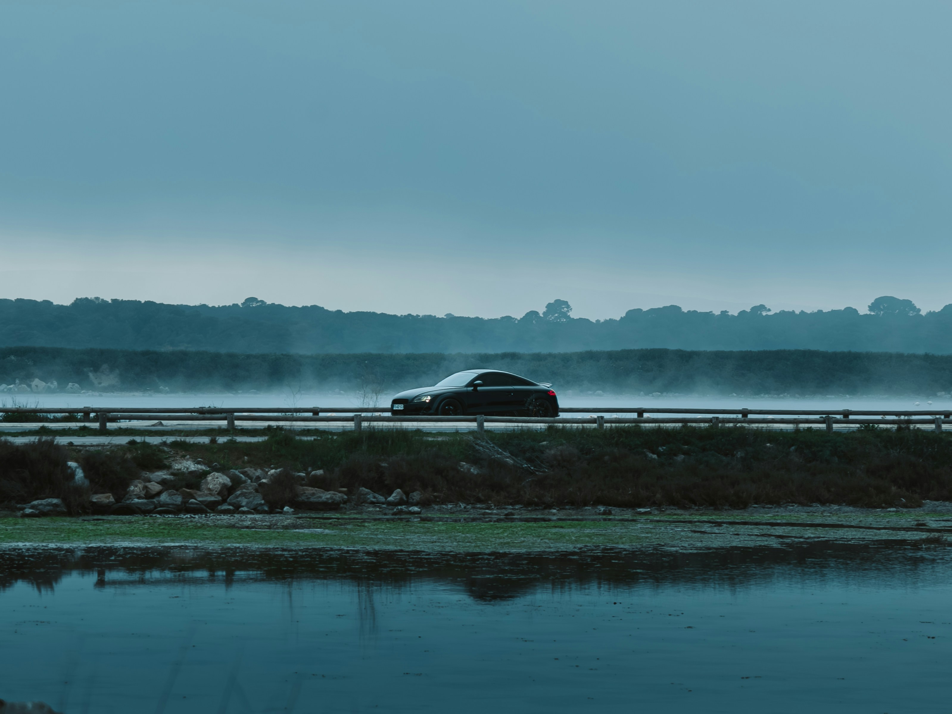 Midday Calm: A Car on the Horizon along a Quiet Waterway