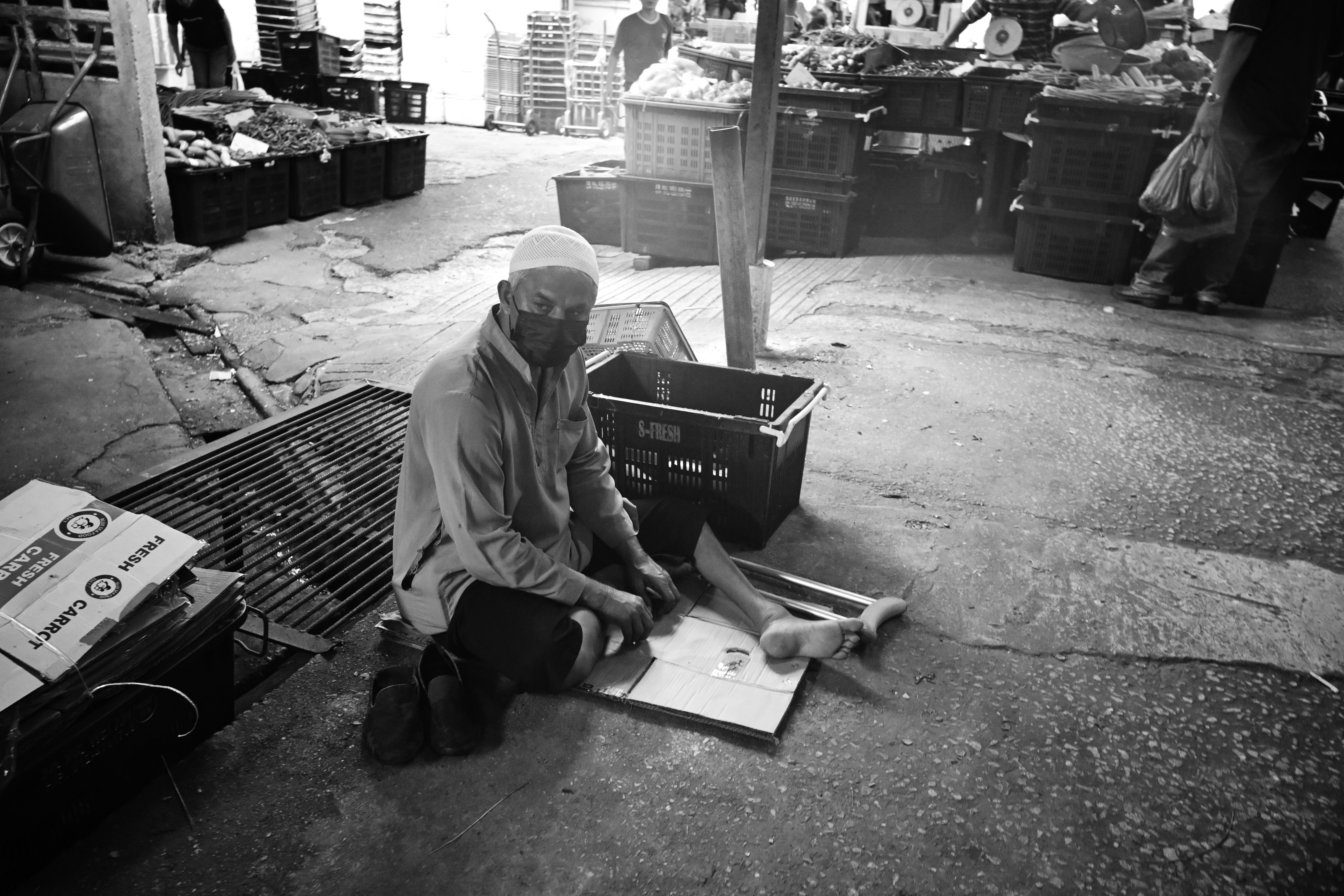 Hushed Market Moment: A Street Vendor Pauses with Paper On the Curb