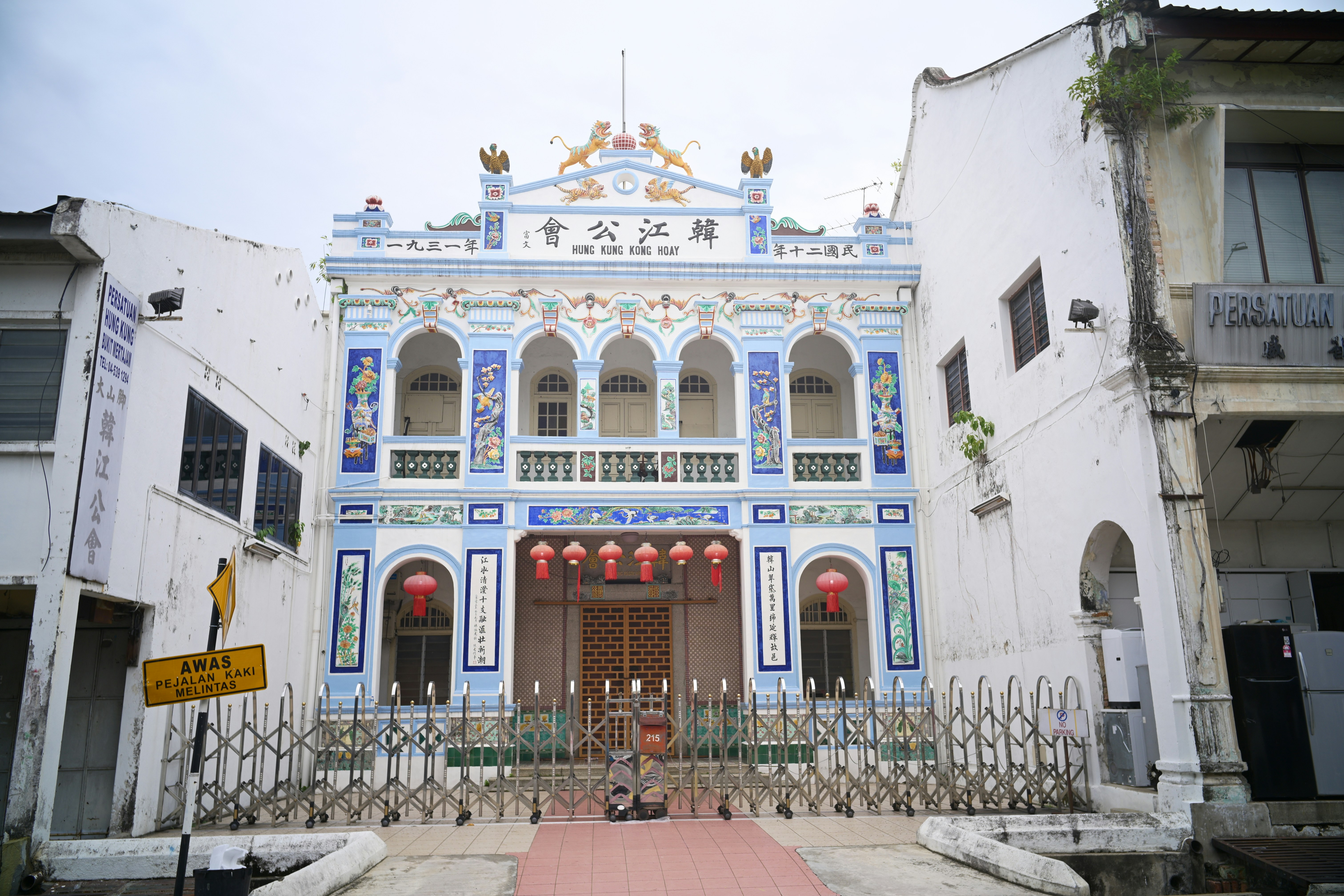 Colorful temple facade framed by white walls and iron gate