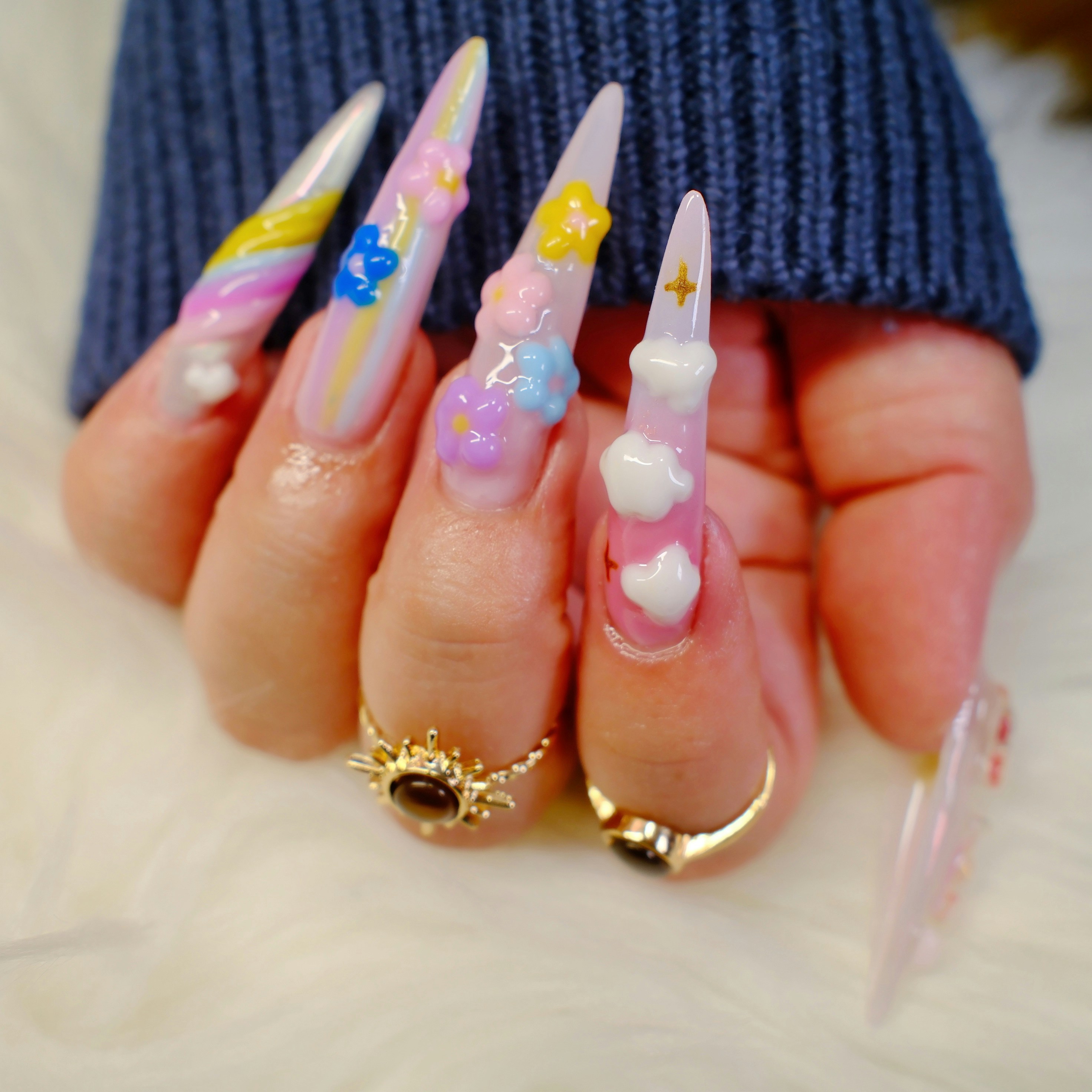 Long, artistic stiletto nails with colorful 3D decorations and rings.