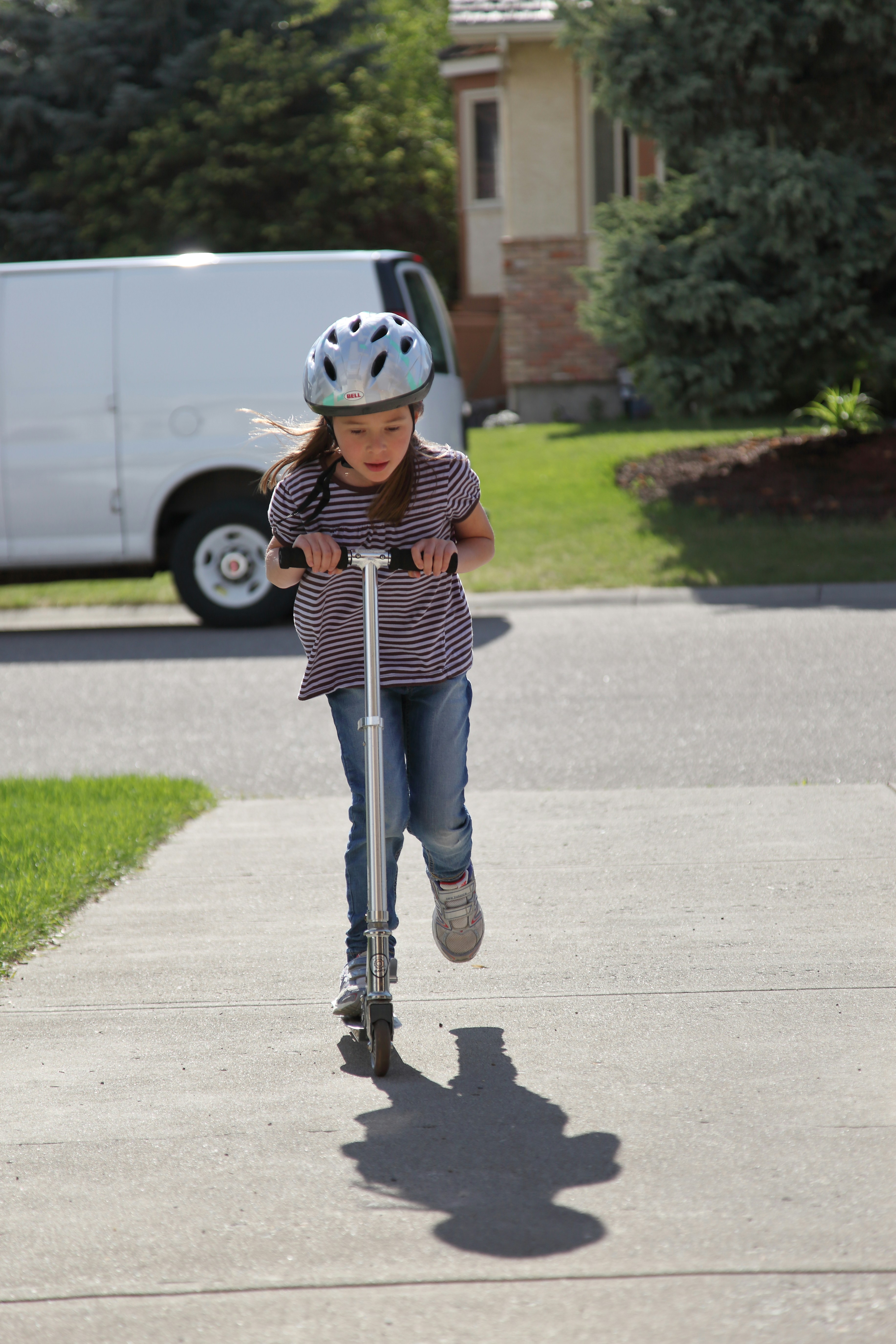 Girl on a Scooter: Focused Fun on a Sunny Sidewalk