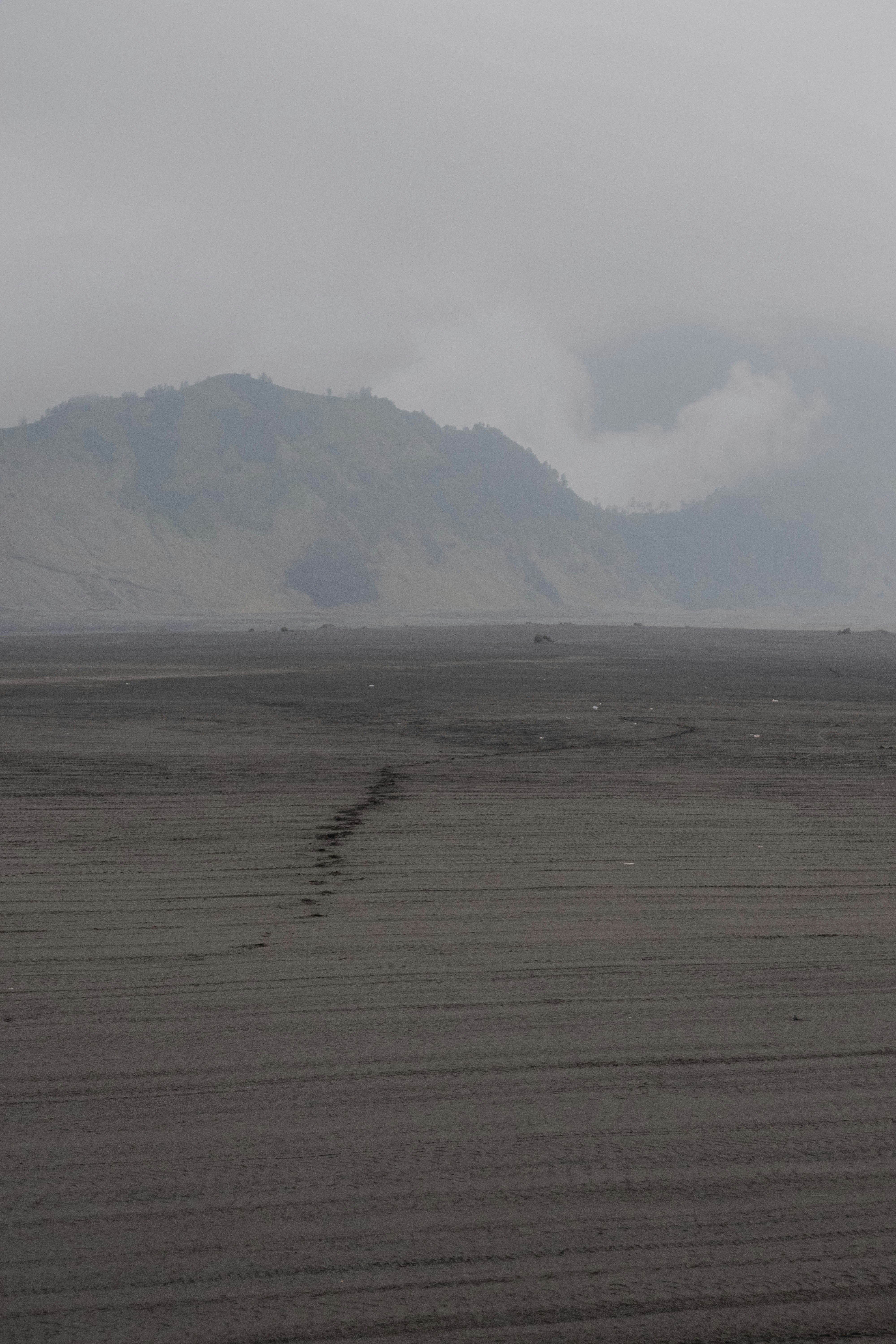 Misty shoreline leading to distant volcanic hills