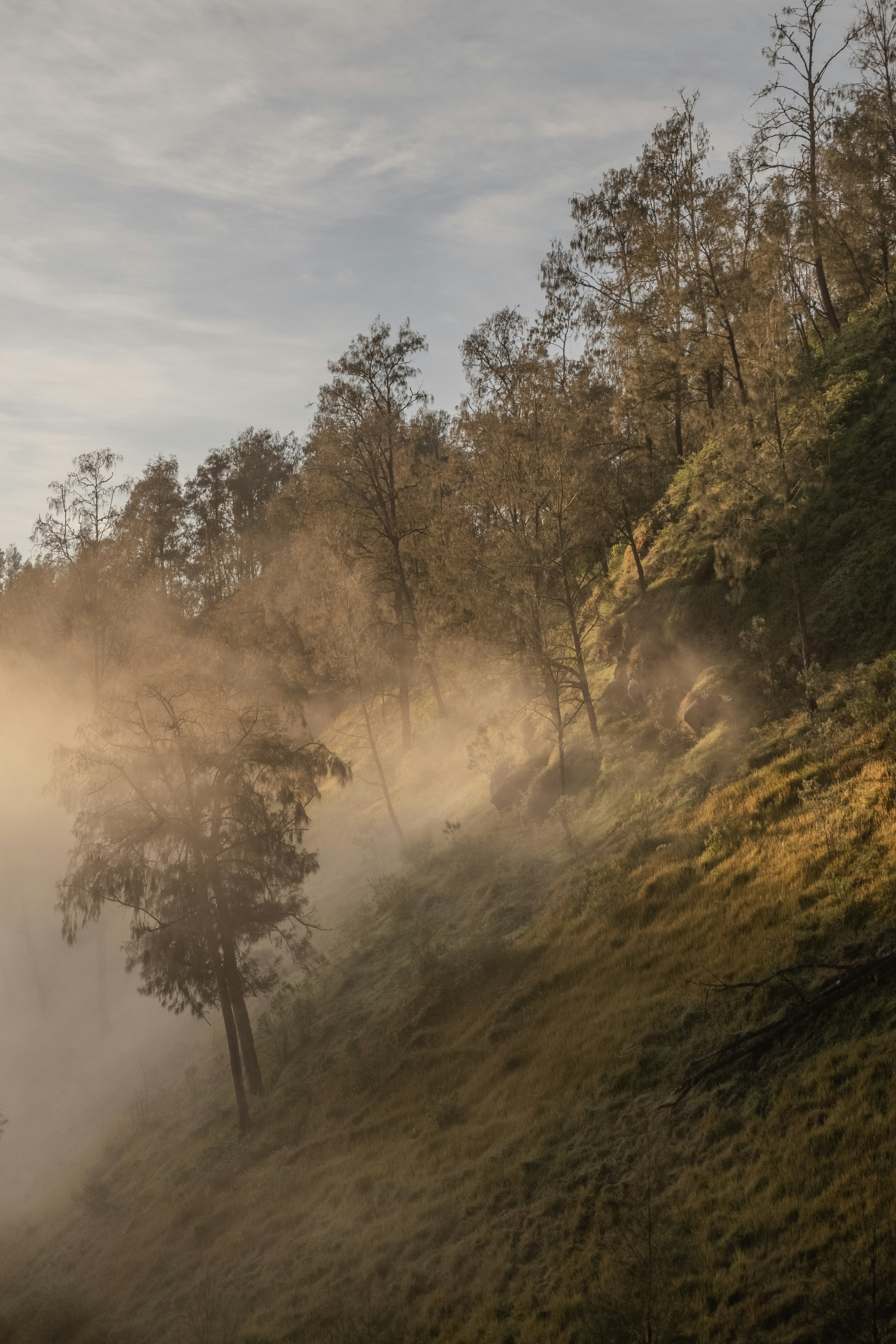 Sun's light piercing through clouds or altogether with cloud enlightening part of a hills near Ranu Kumbolo Lake, during sunrise.