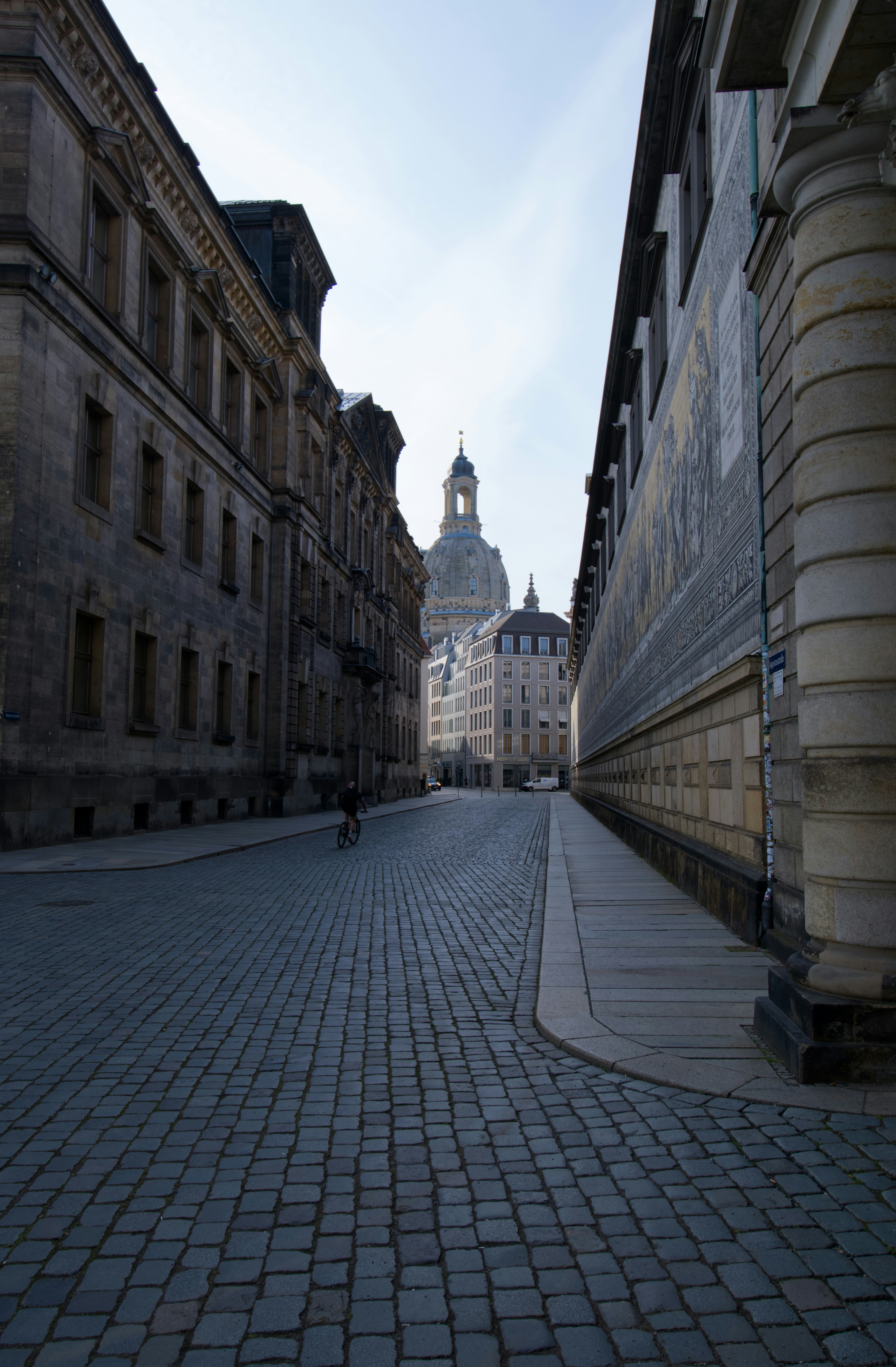 Streetside Cathedral View: A Quiet Cobblestone Corridor Toward a Distant Dome