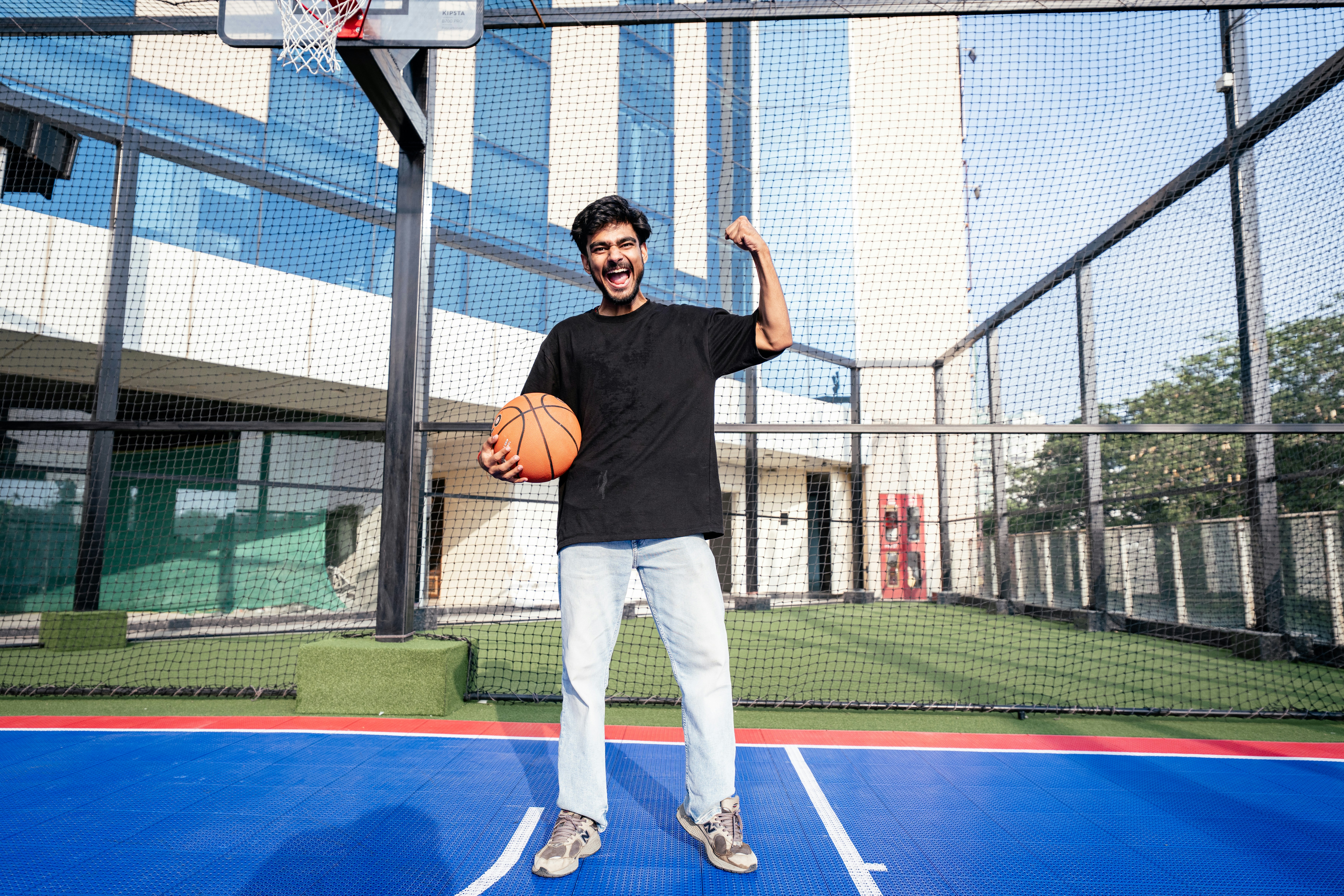 Courtside Leap: A Basketball Player Rejoices on a Sunlit Outdoor Court