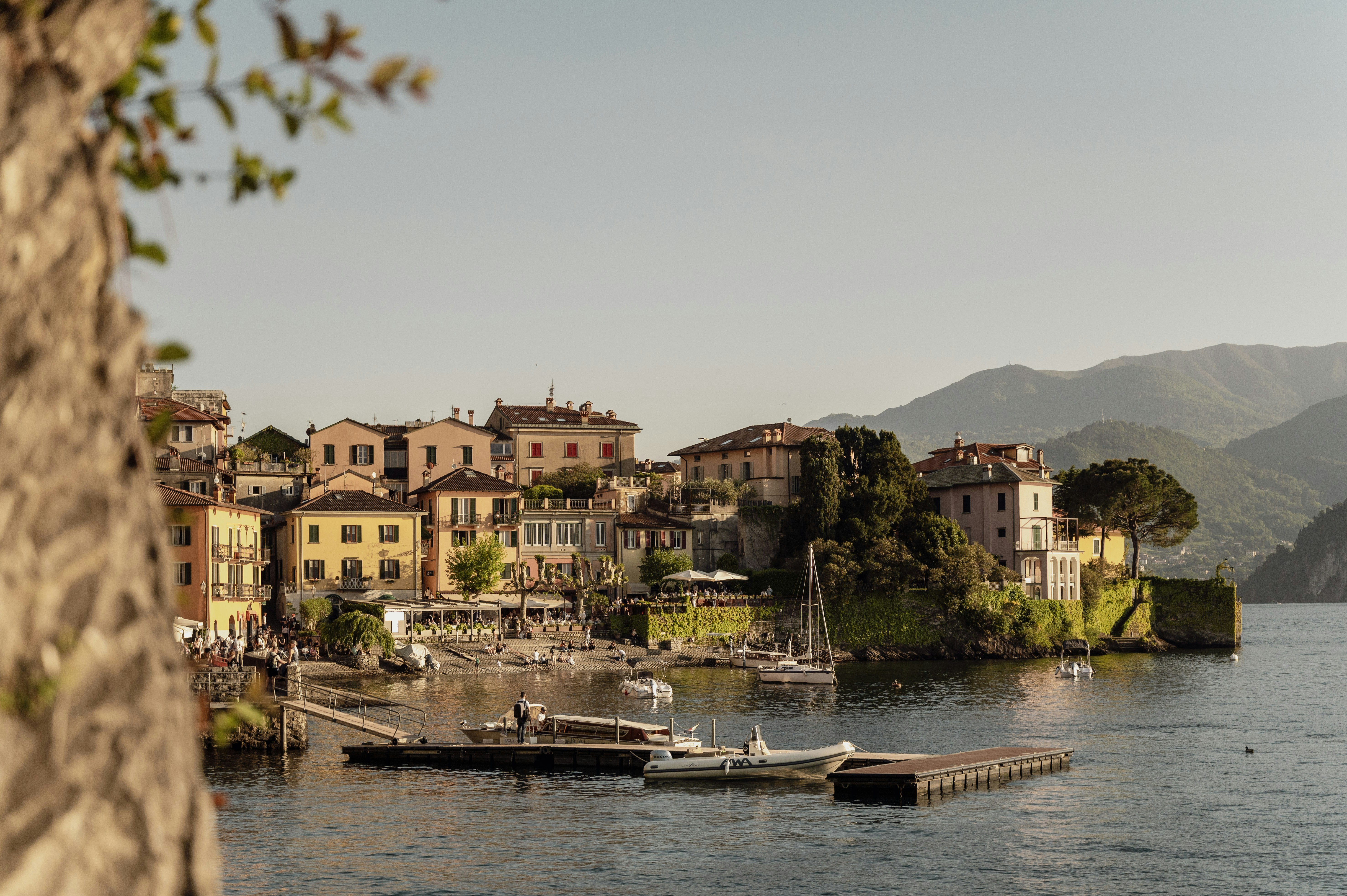 A picturesque town on a lake with boats and mountains.