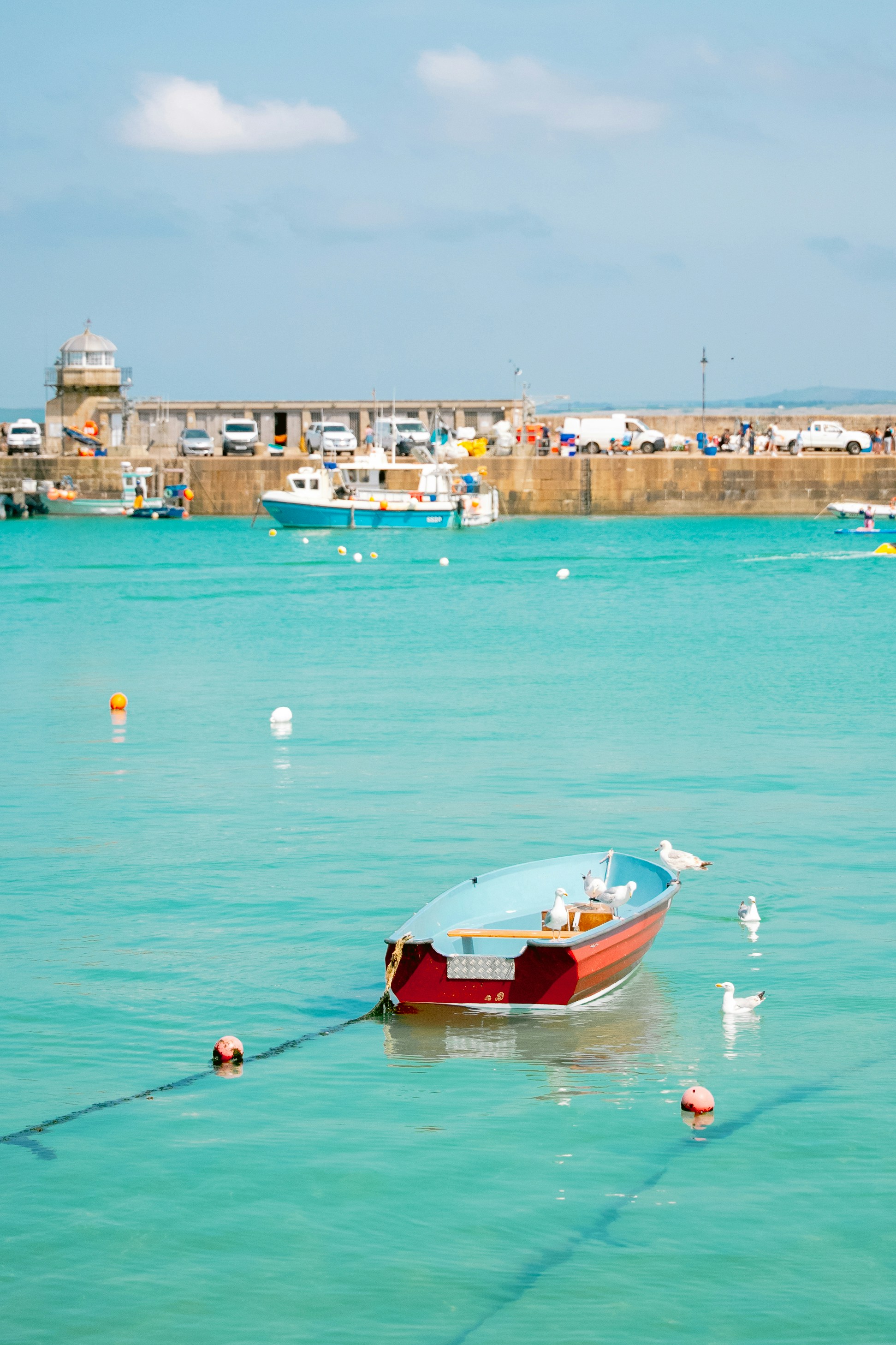 A Teal Harbor: A Red Boat Anchored in Calm Coastal Waters