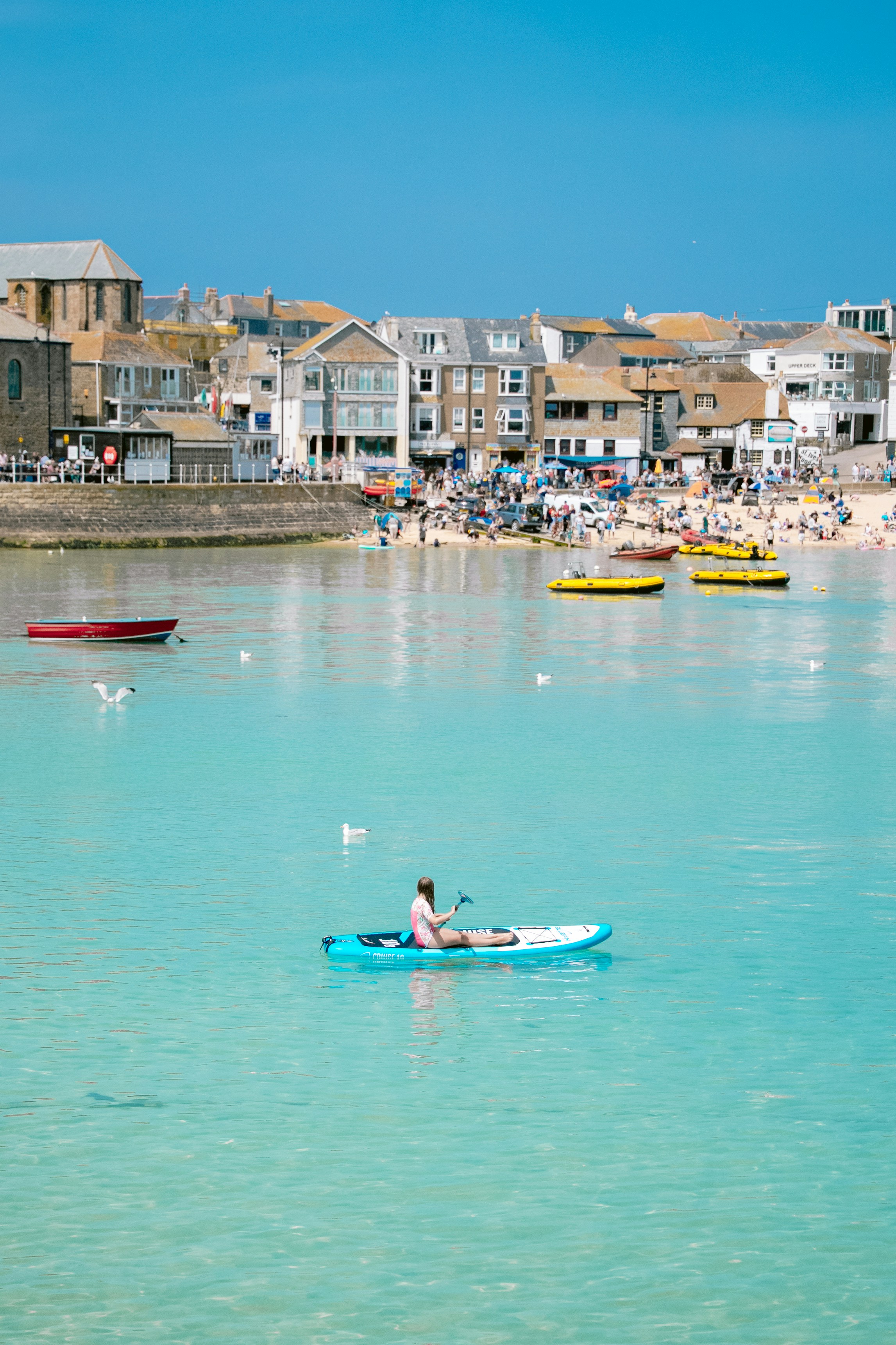Turquoise Waters and a Distant Village: A Paddleboarder’s Quiet Moment