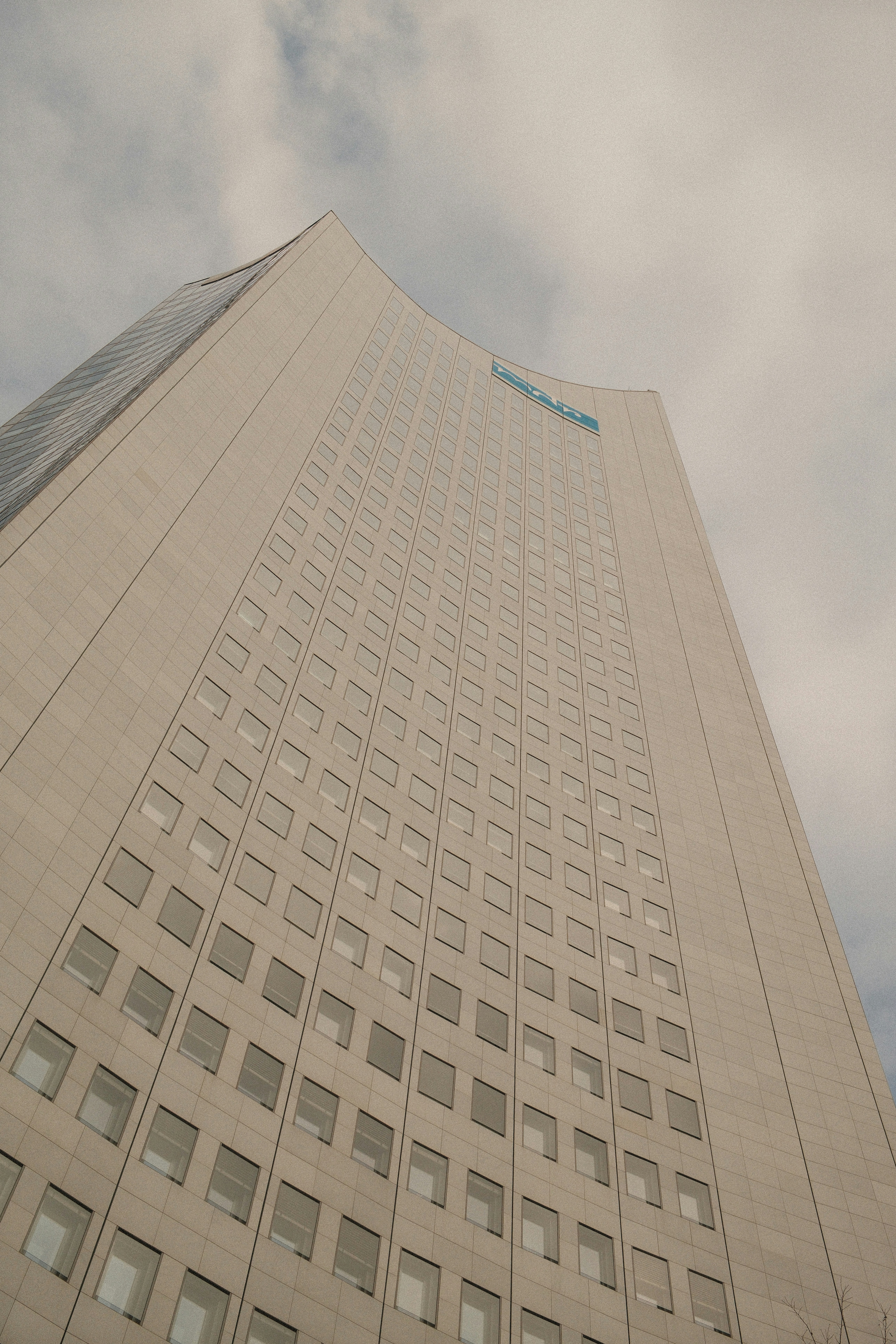 Vertical Facade: A Distant Skyscraper Reaching Toward a Clouded Sky
