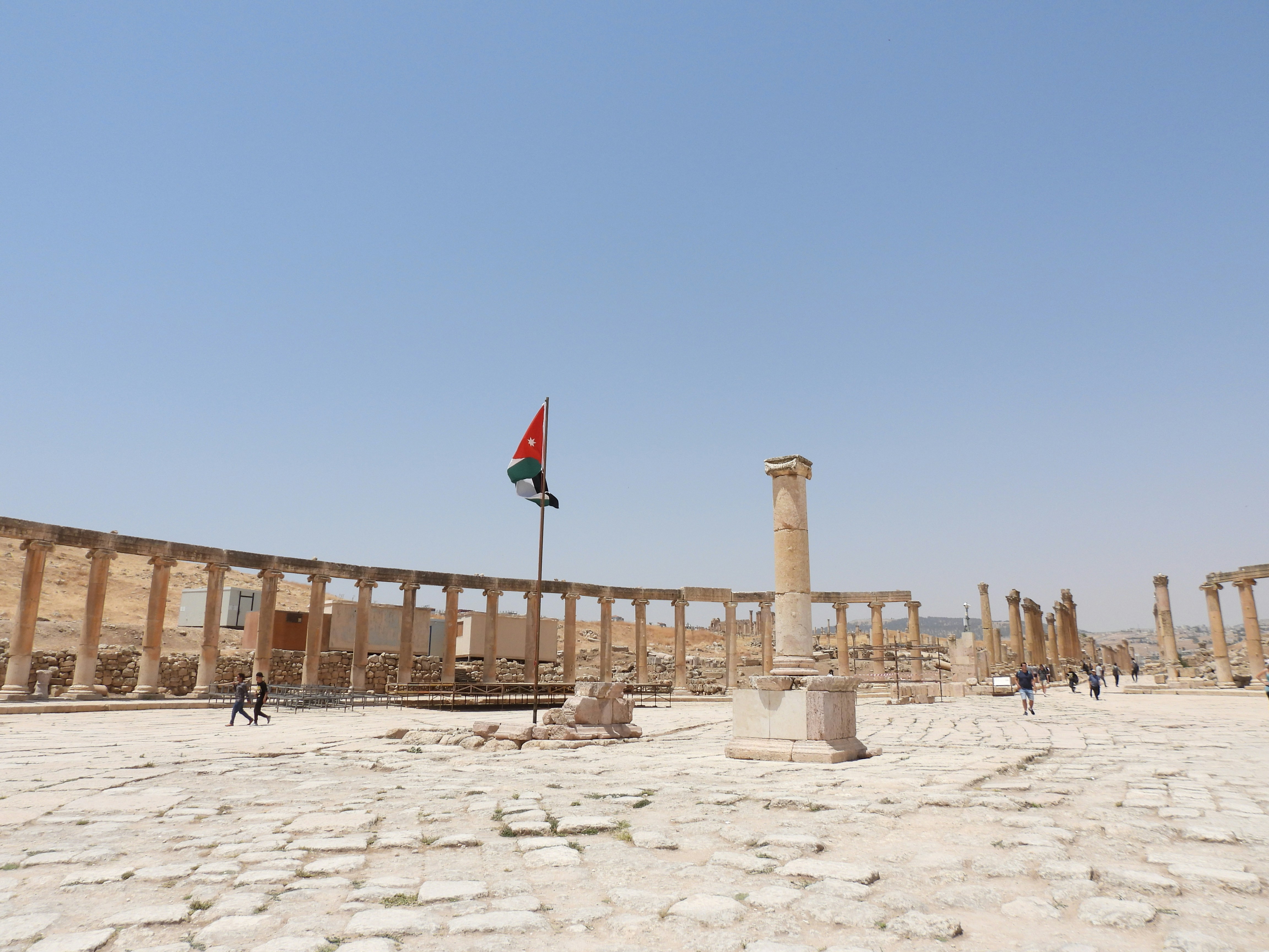 Flag above ancient columns in sunlit Jordanian ruin