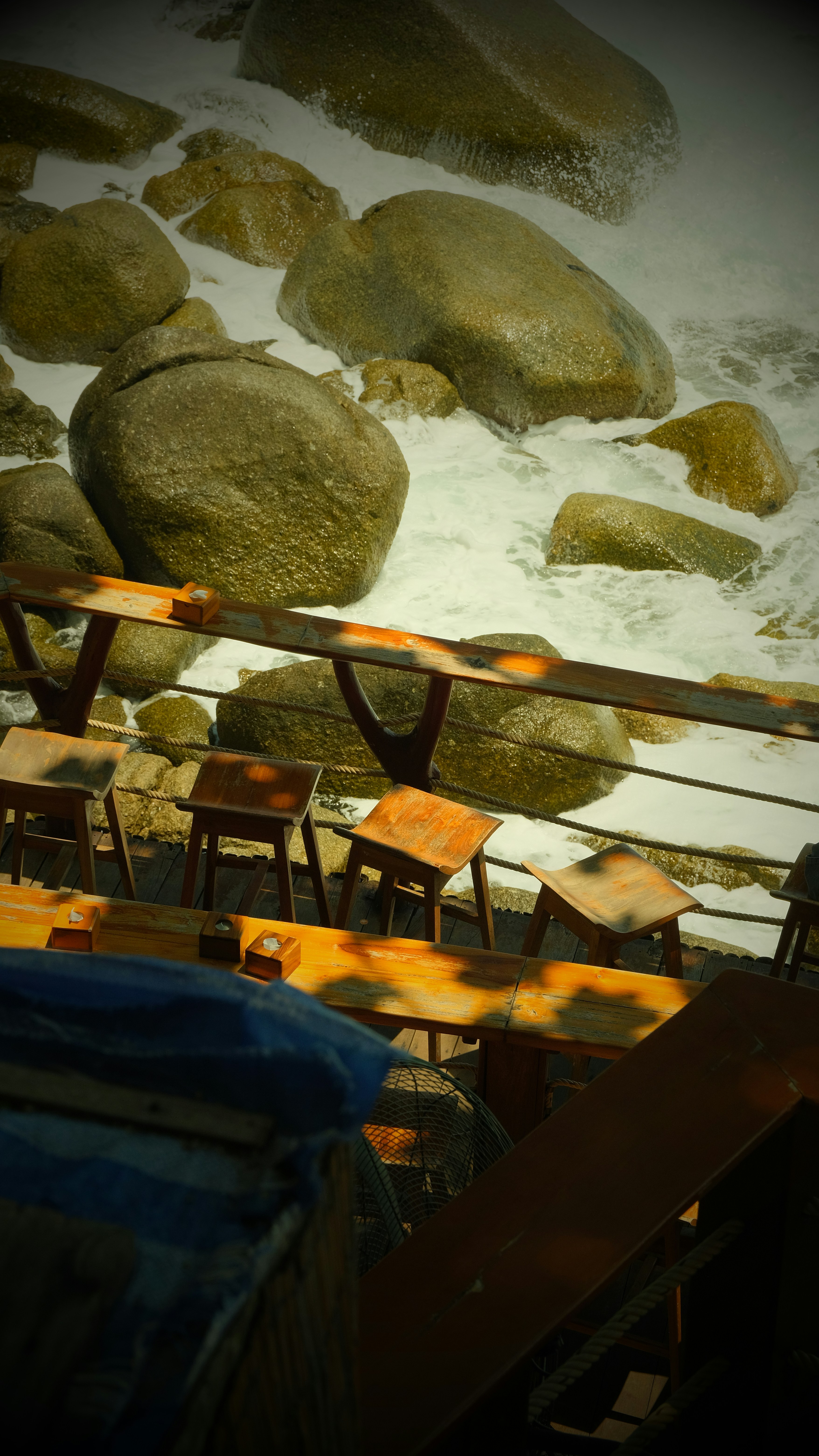 Rusted railing and wooden benches overlook a rocky shoreline