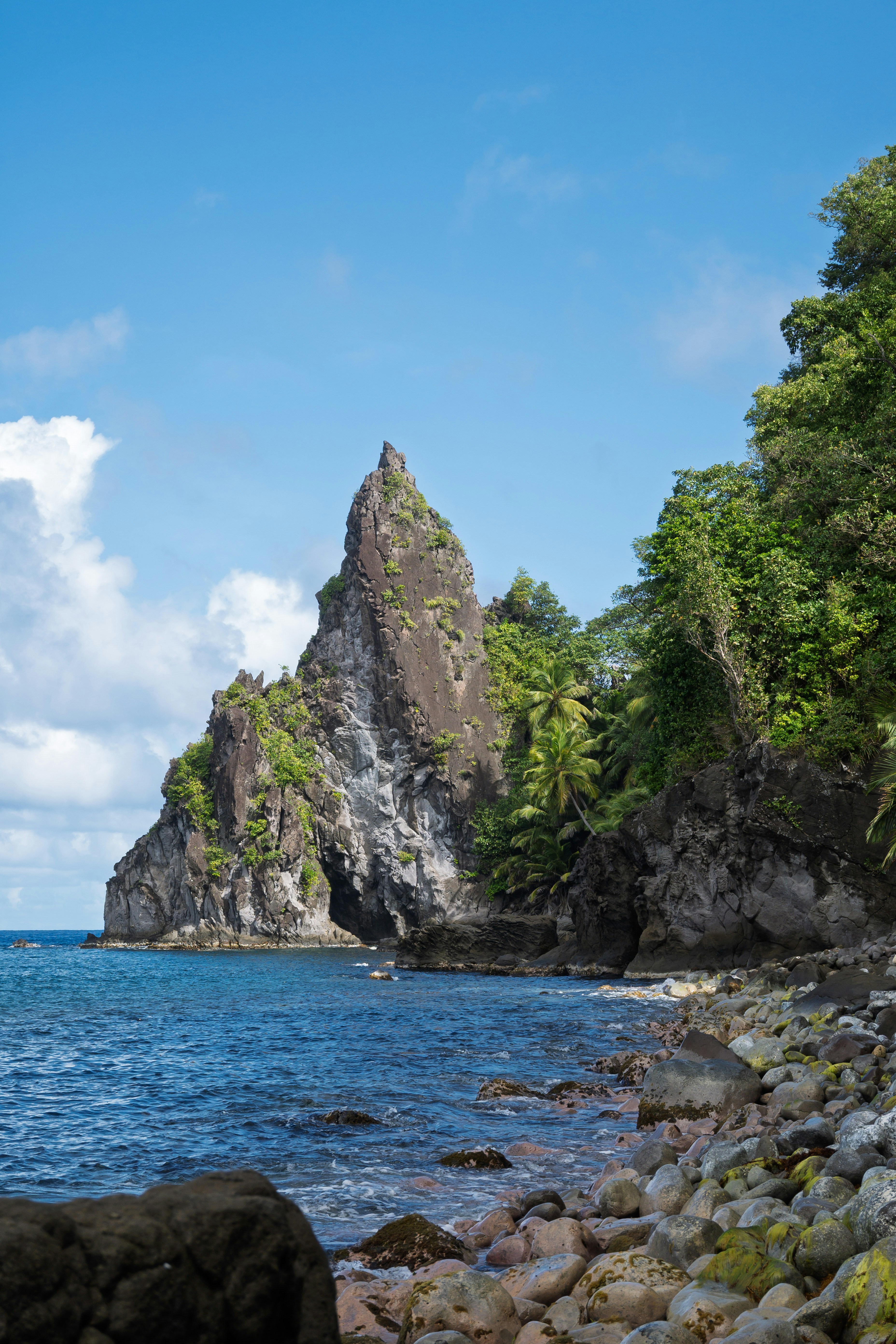 Tropical coastline with a majestic rock formation and rocky beach.