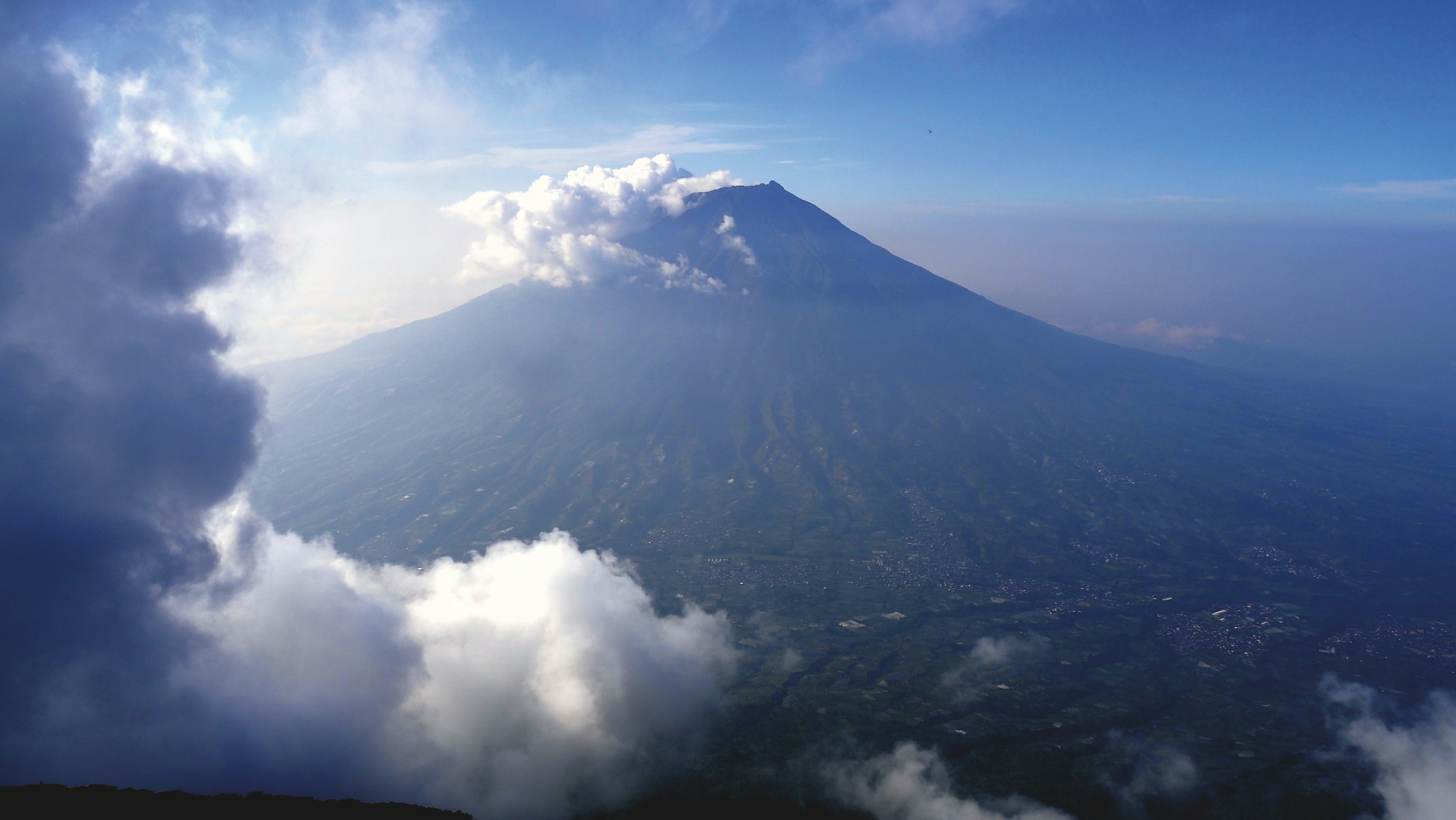 Aerial Summit: Cloud-Wrapped Volcanic Peak Rising Above a Valley