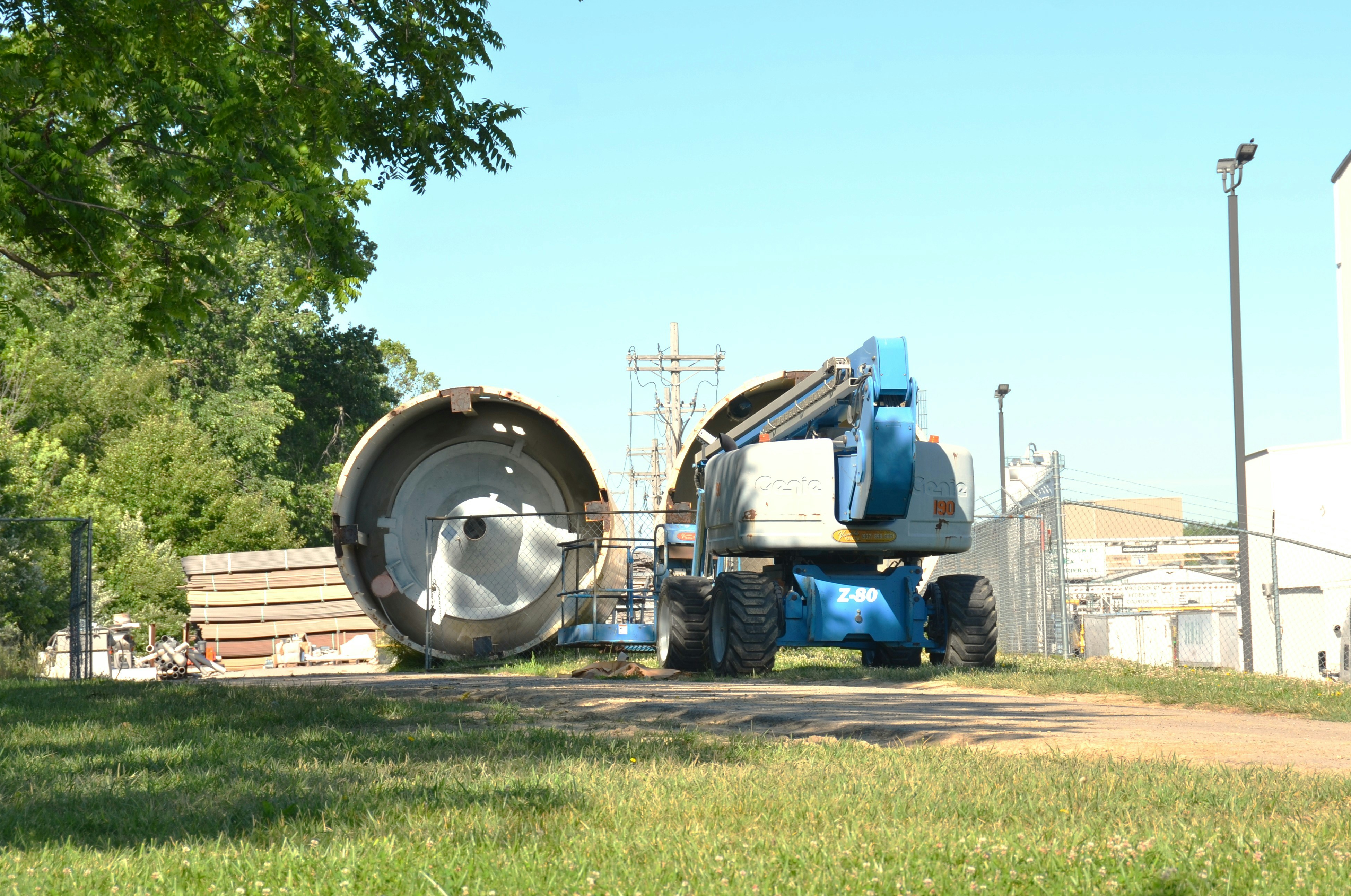 Crane and Circular Concrete Pipe at a Sunny Construction Yard