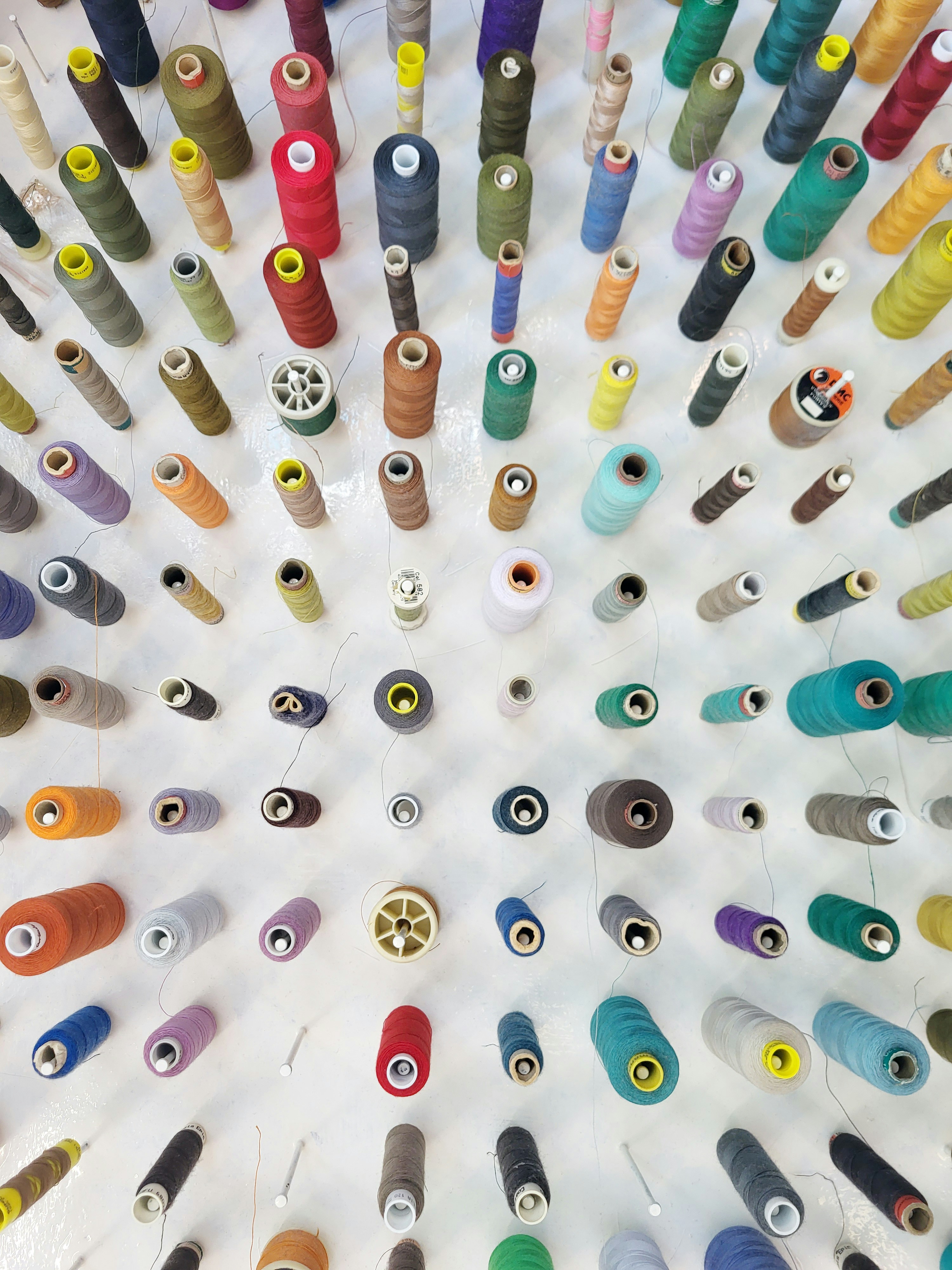 Many colorful spools of thread arranged on a white surface.