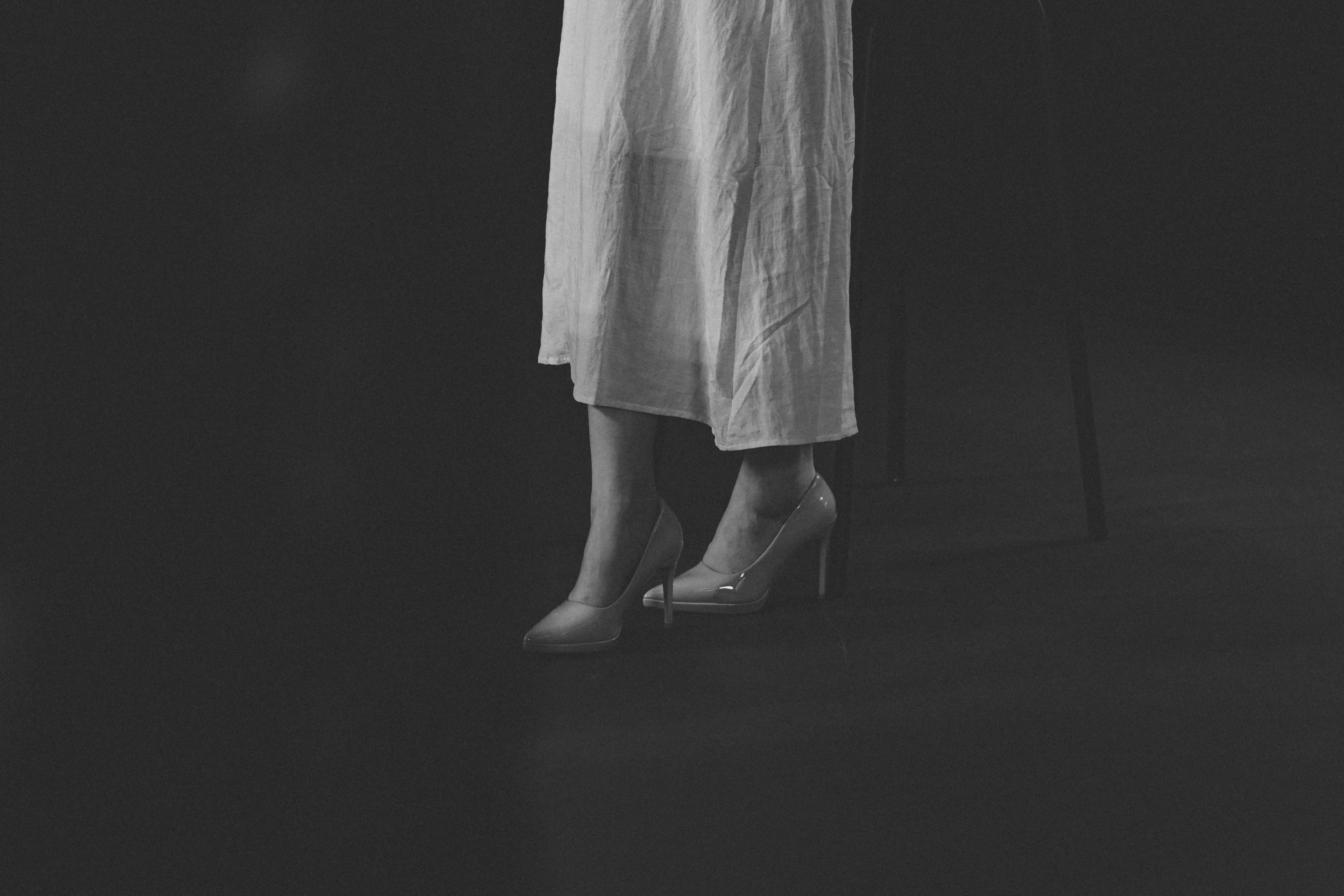 Woman's legs and high heels against a dark background.