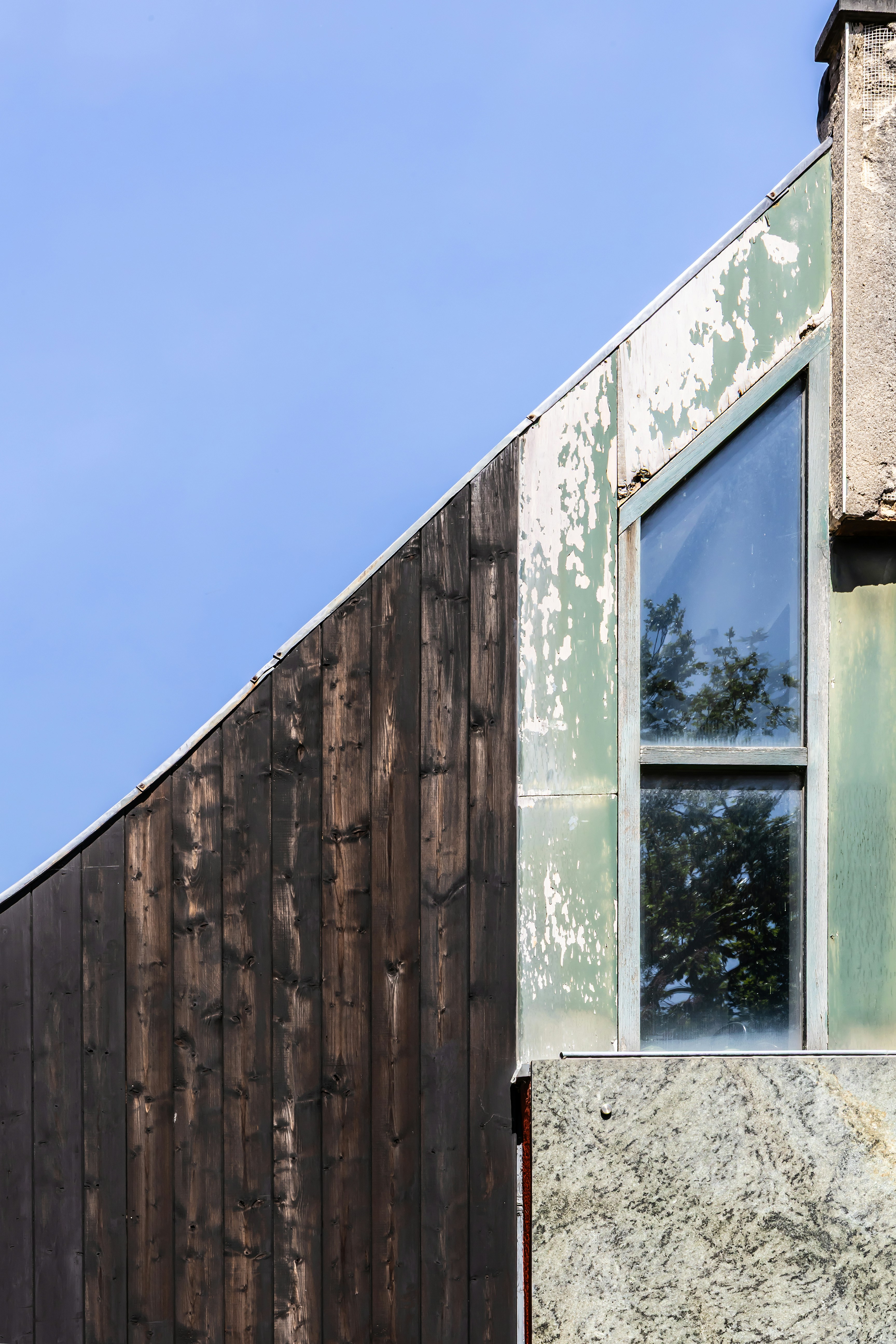 Abstract architecture: weathered wood, peeling paint, and a triangular window.