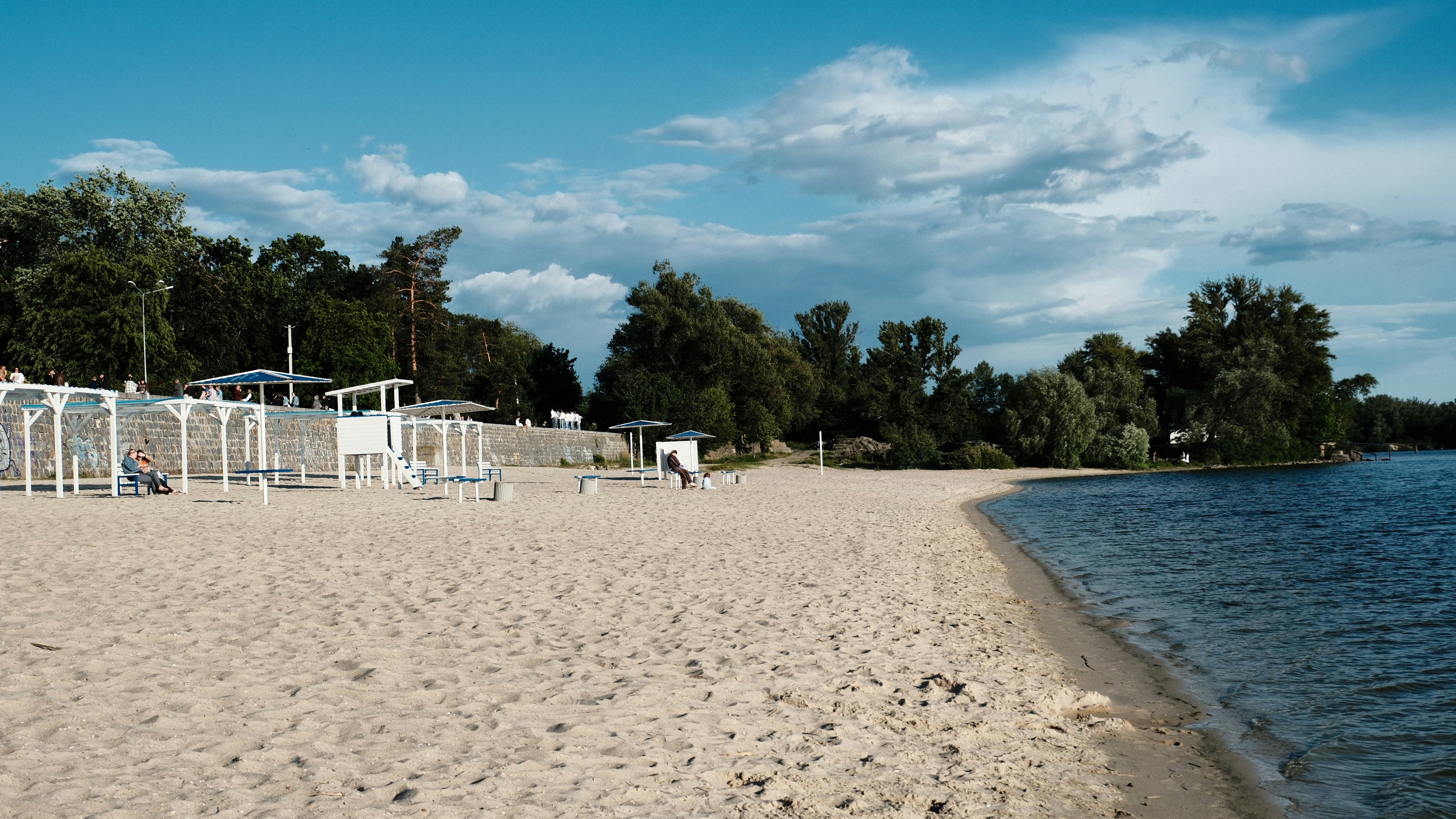 Quiet shoreline: a sunlit beach with shaded cabanas and calm water