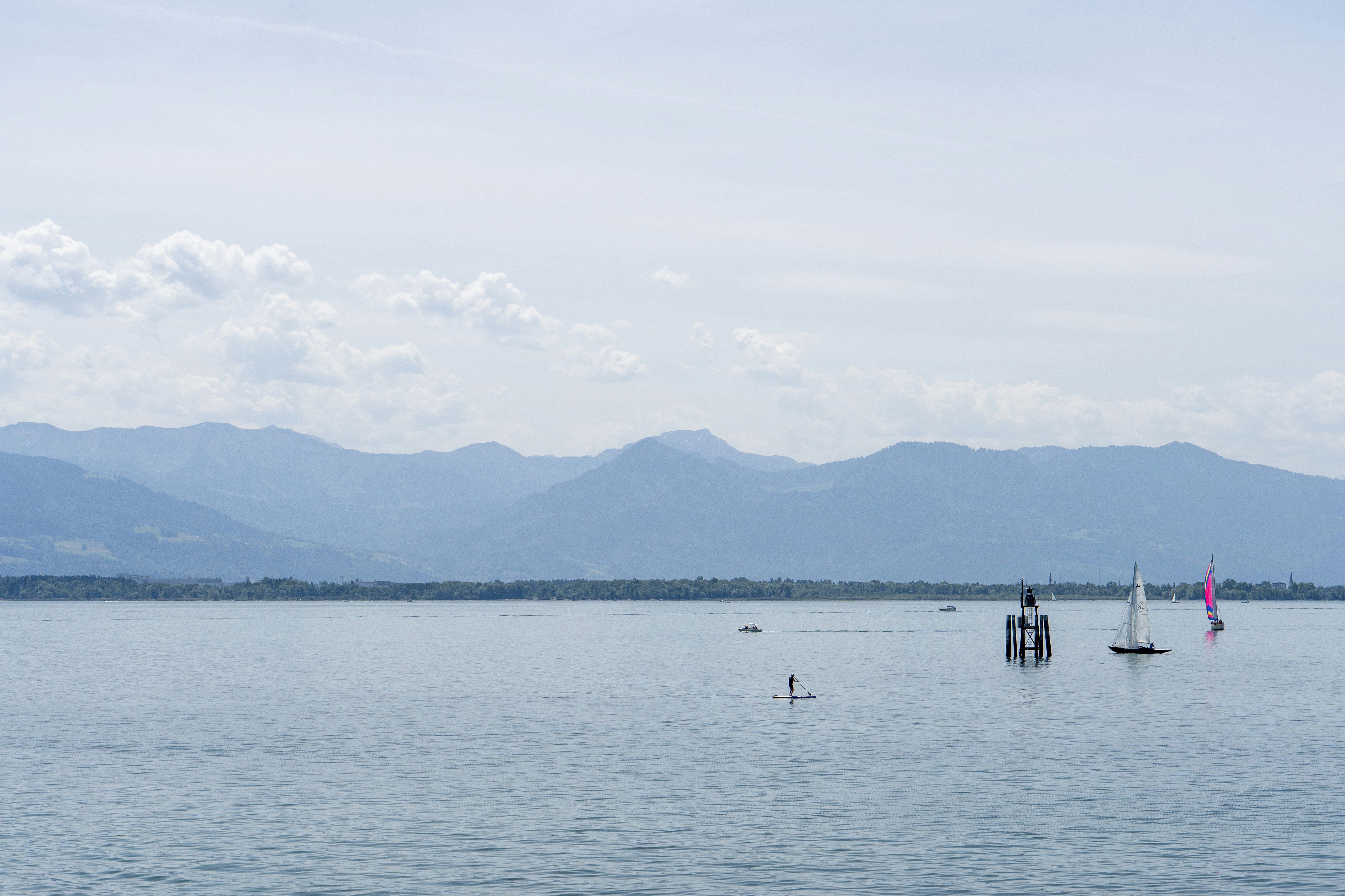 Calm Lake, Distant Mountains, and Sailboats at Dusk