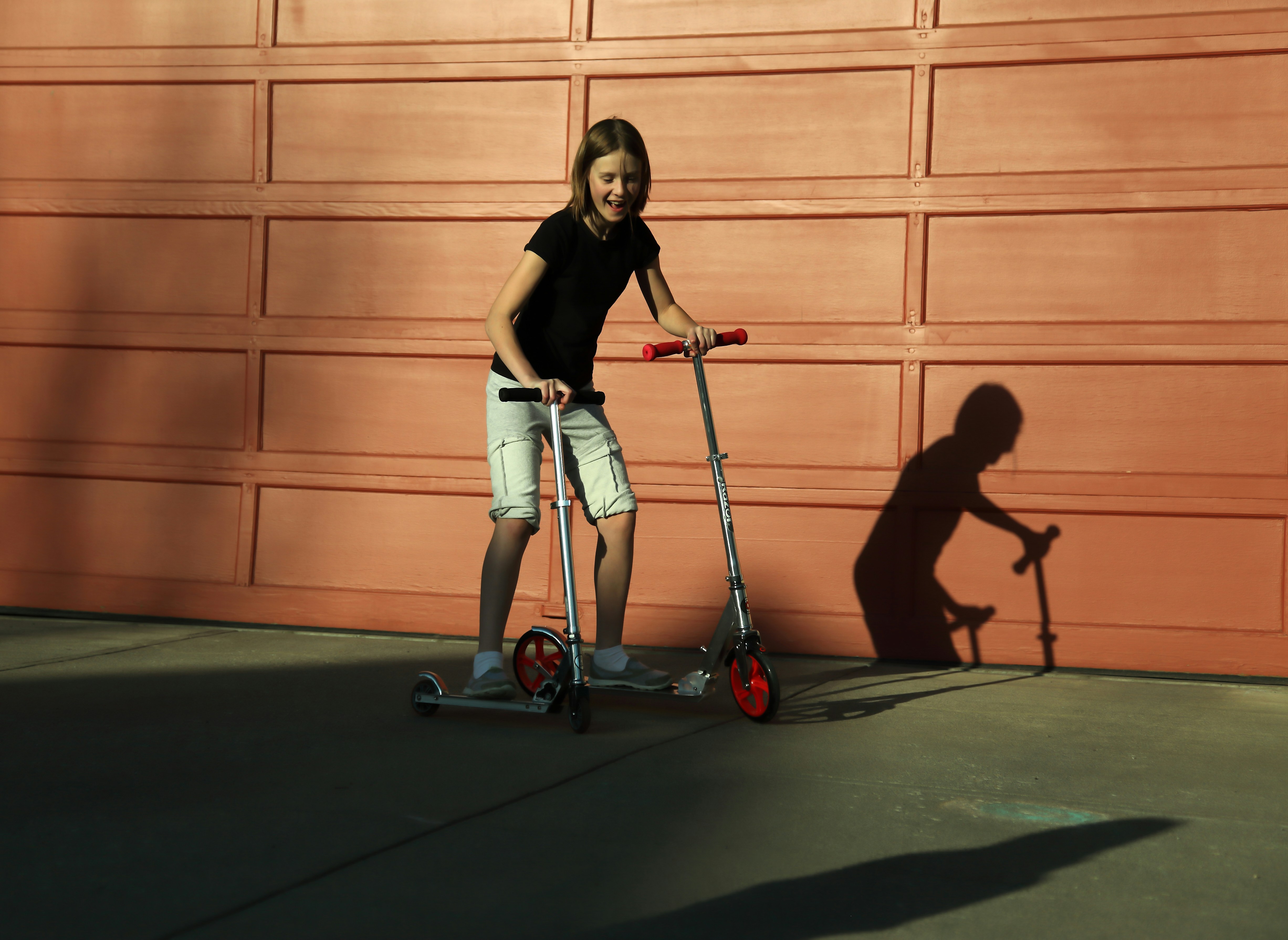 Girl on a Scooter in Front of a Red Wall