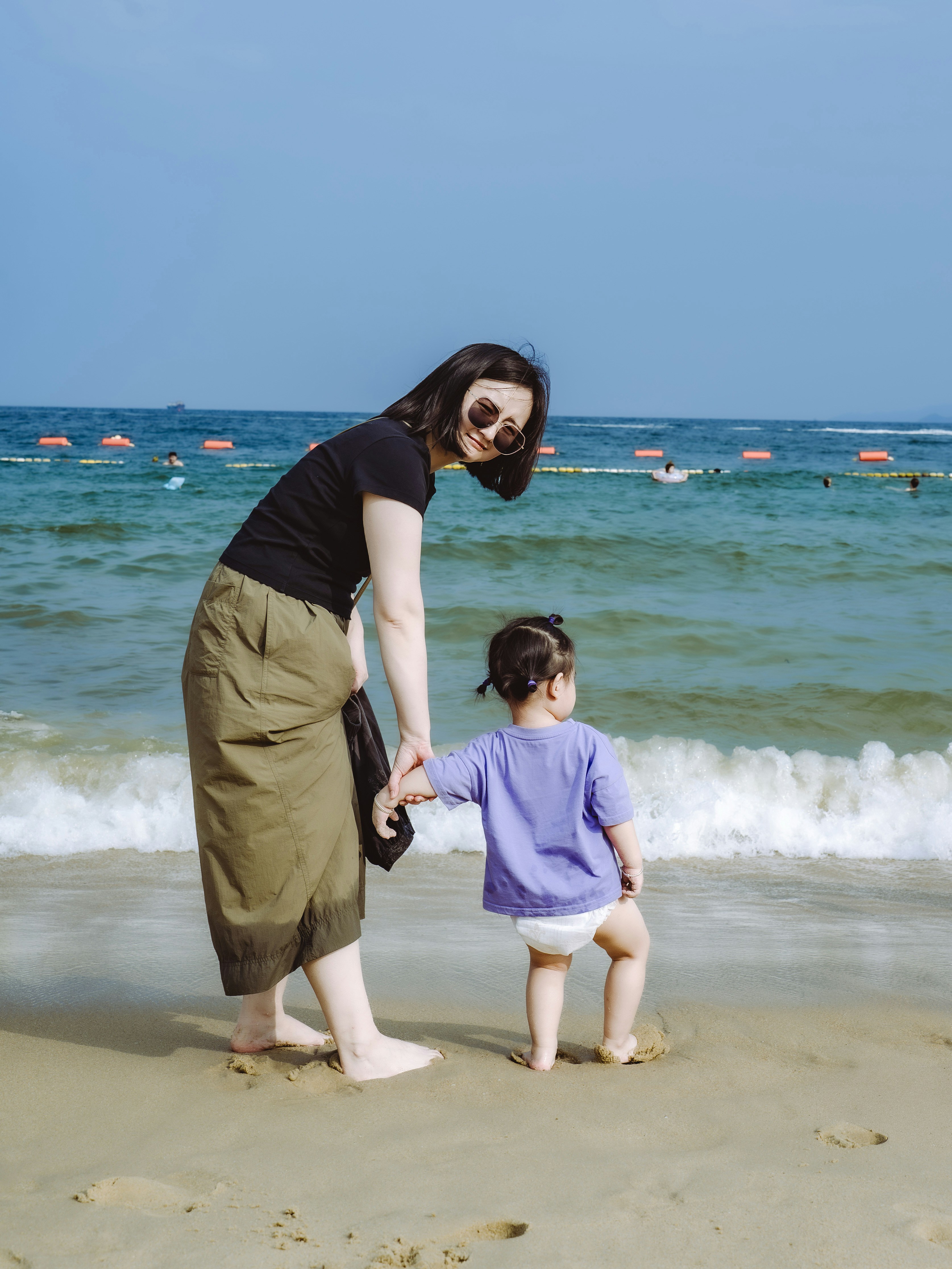 Holding Hands on the Shore: A Mother and Child Amid Gentle Waves