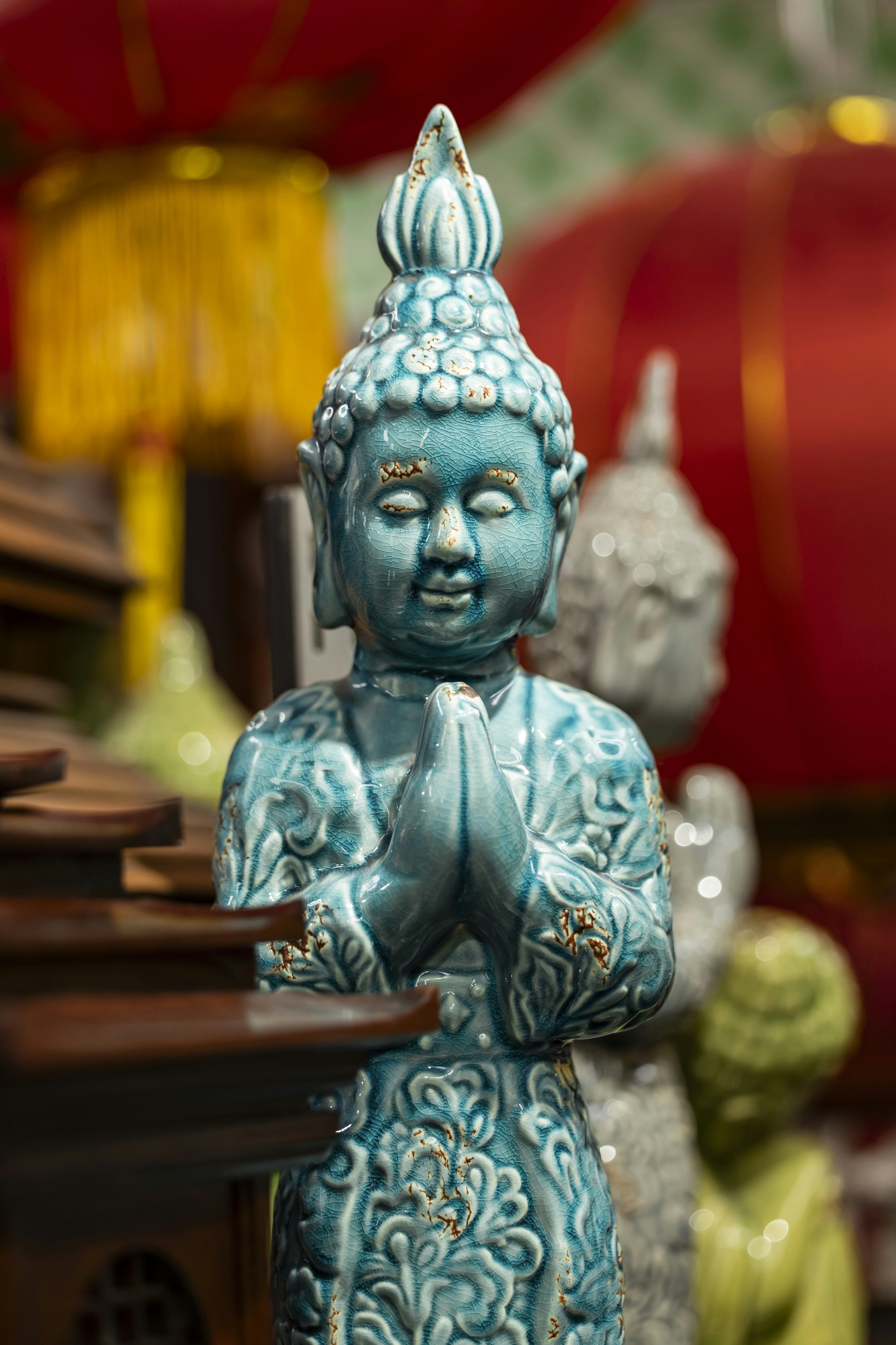 Blue ceramic buddha statue in prayer pose.