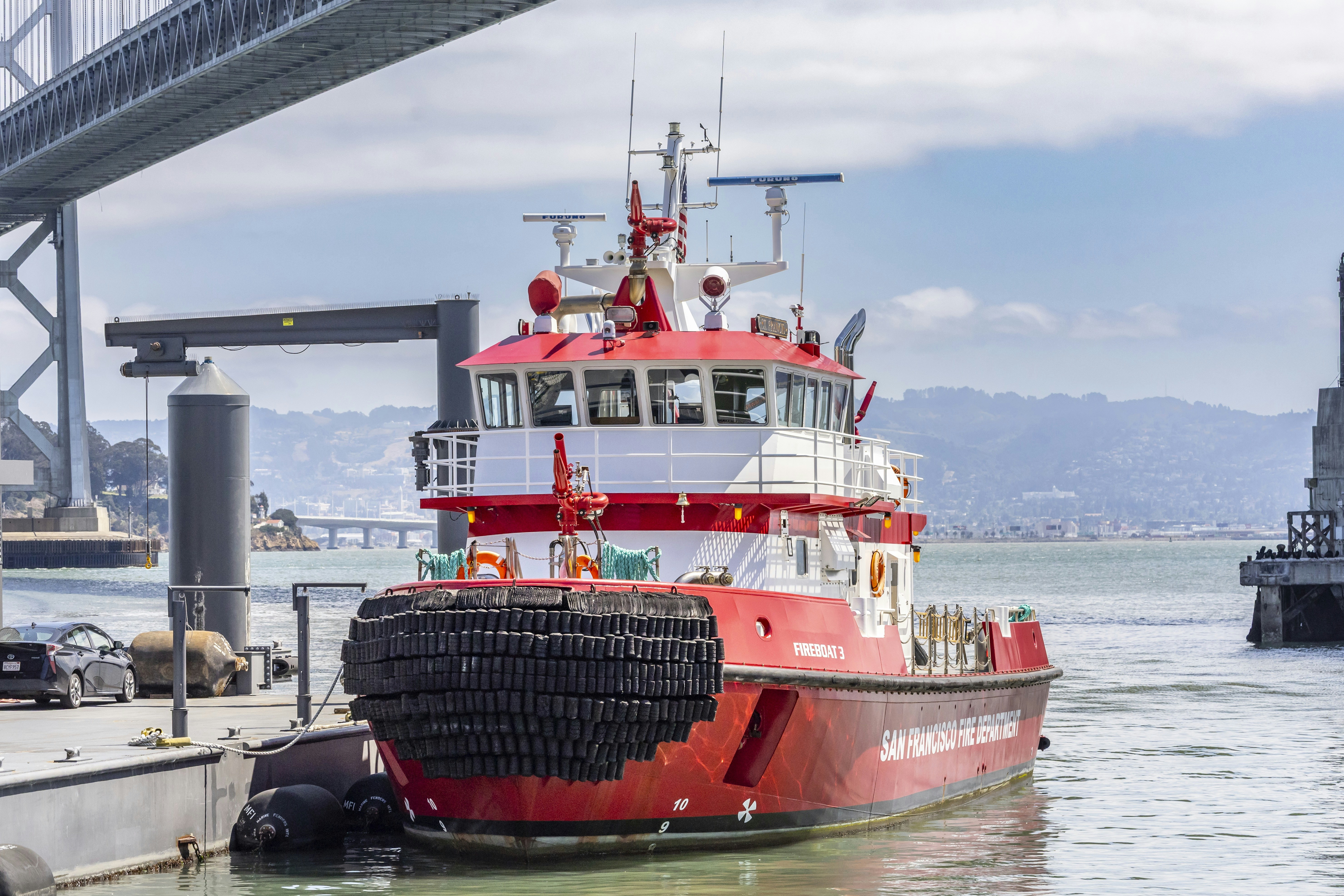 A red and white boat docked under a bridge.