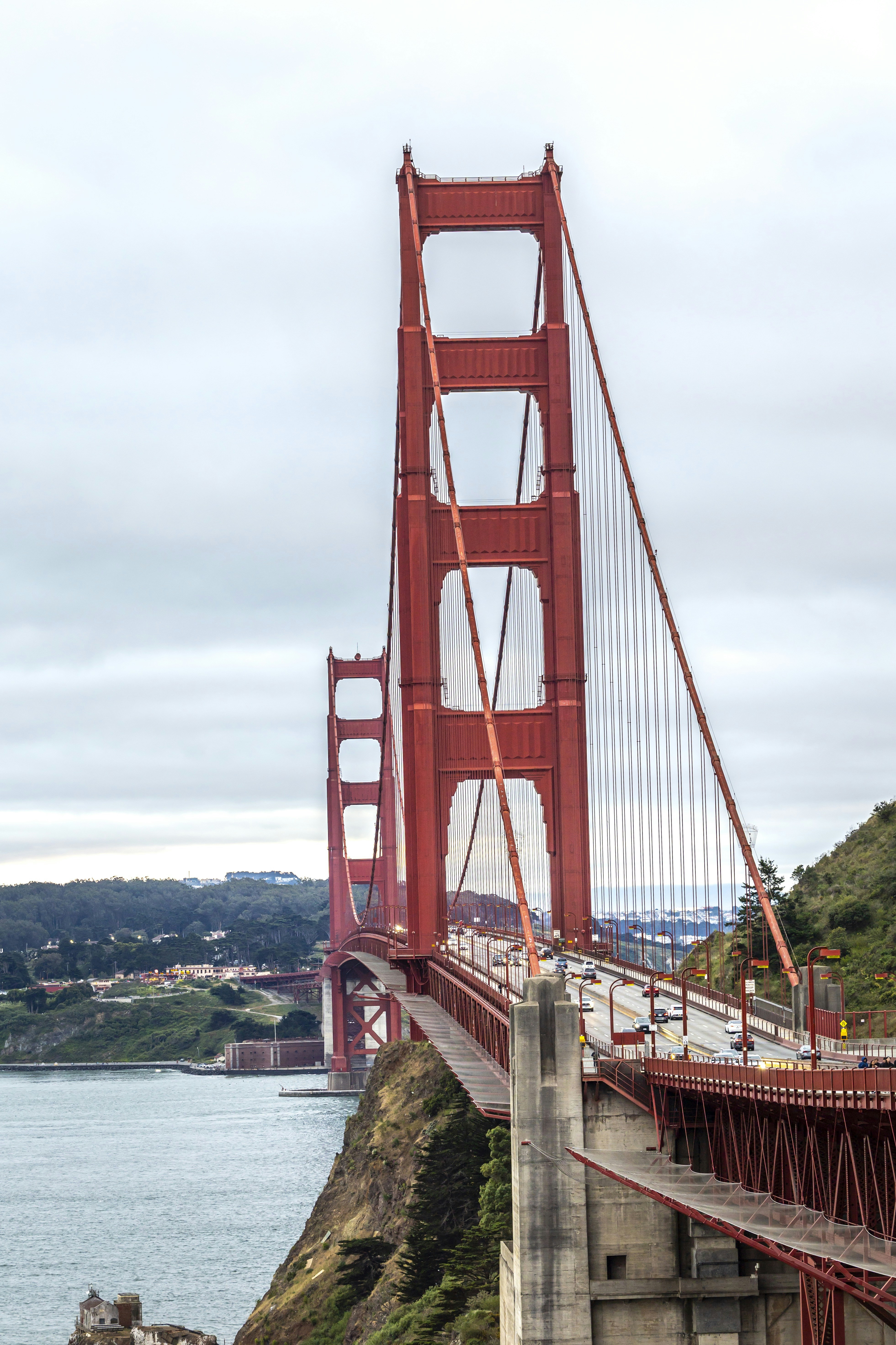 Golden gate bridge spanning water under a cloudy sky.