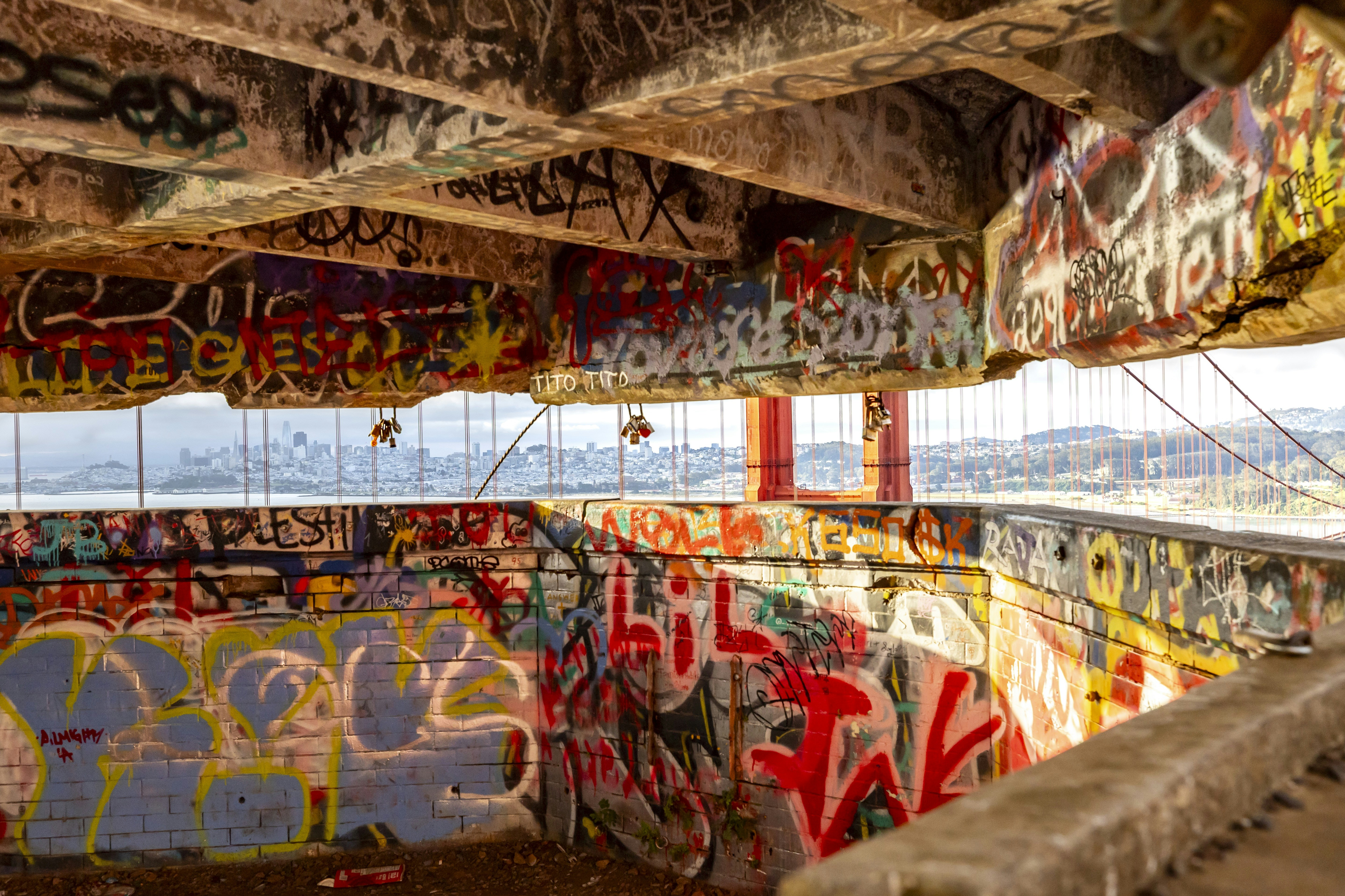 Concrete structure covered in vibrant graffiti with distant city view.