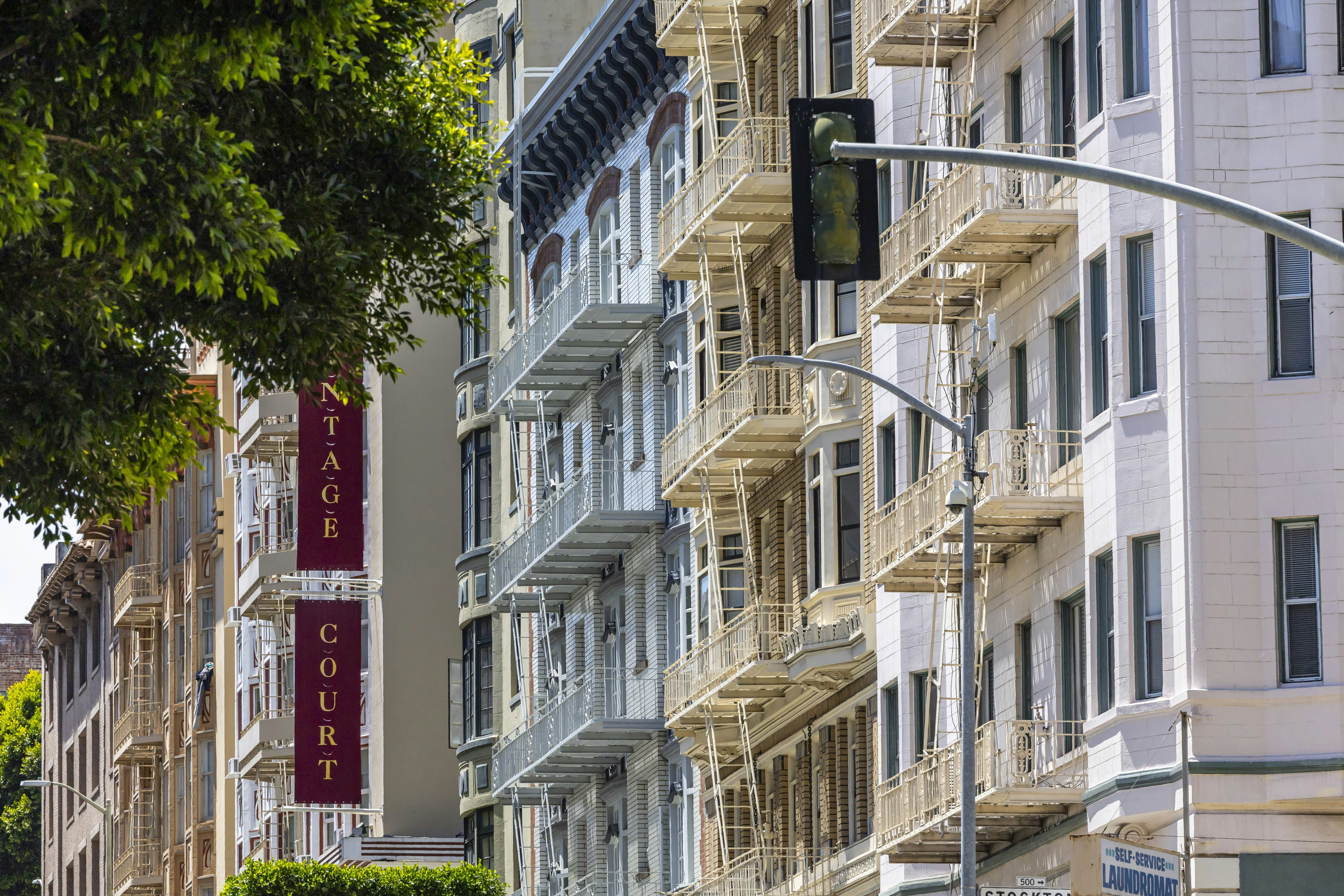 Historic city buildings with balconies and a traffic light.