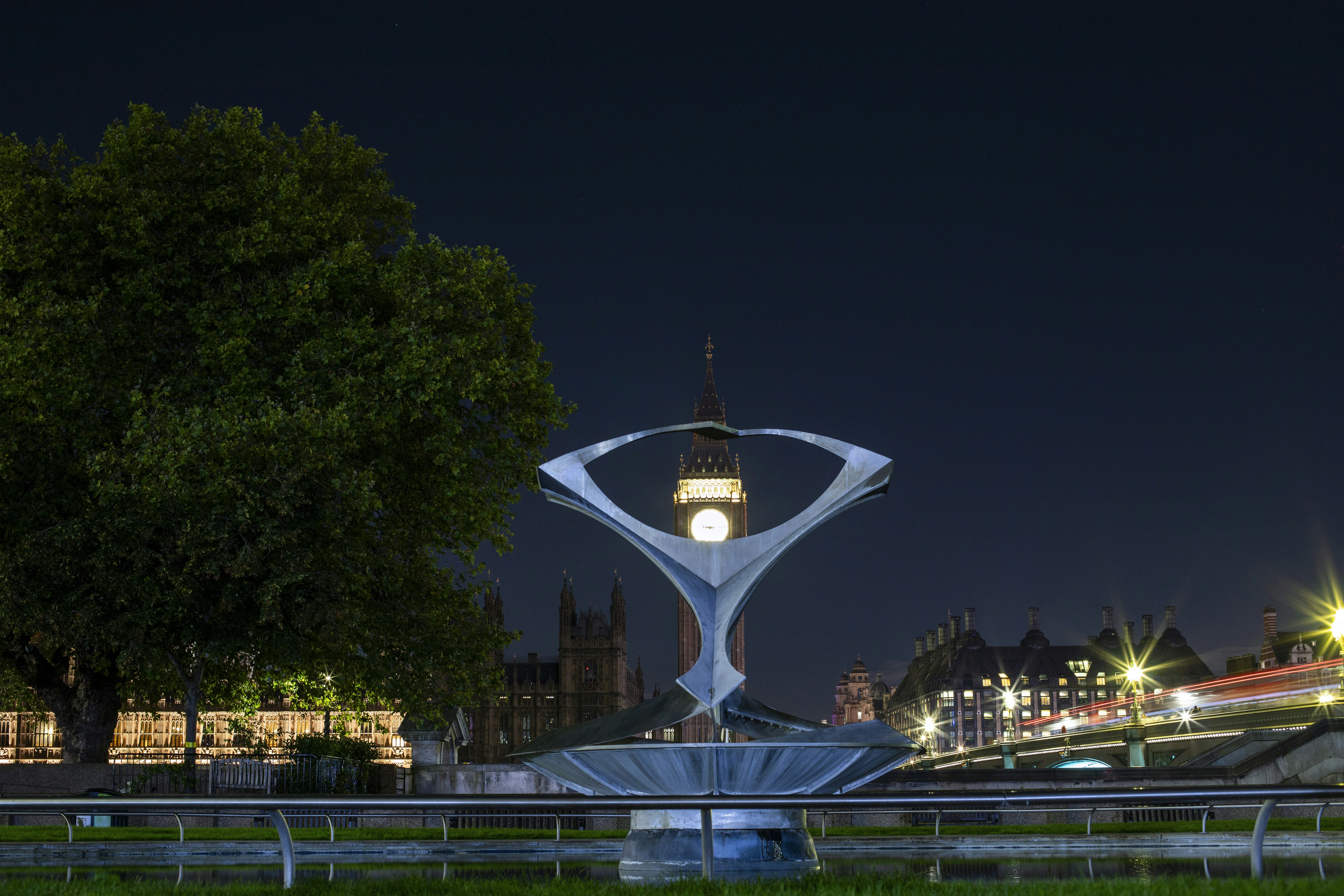 Clocktower Mirage: The Arching Fountain Sculpture Framed by Night