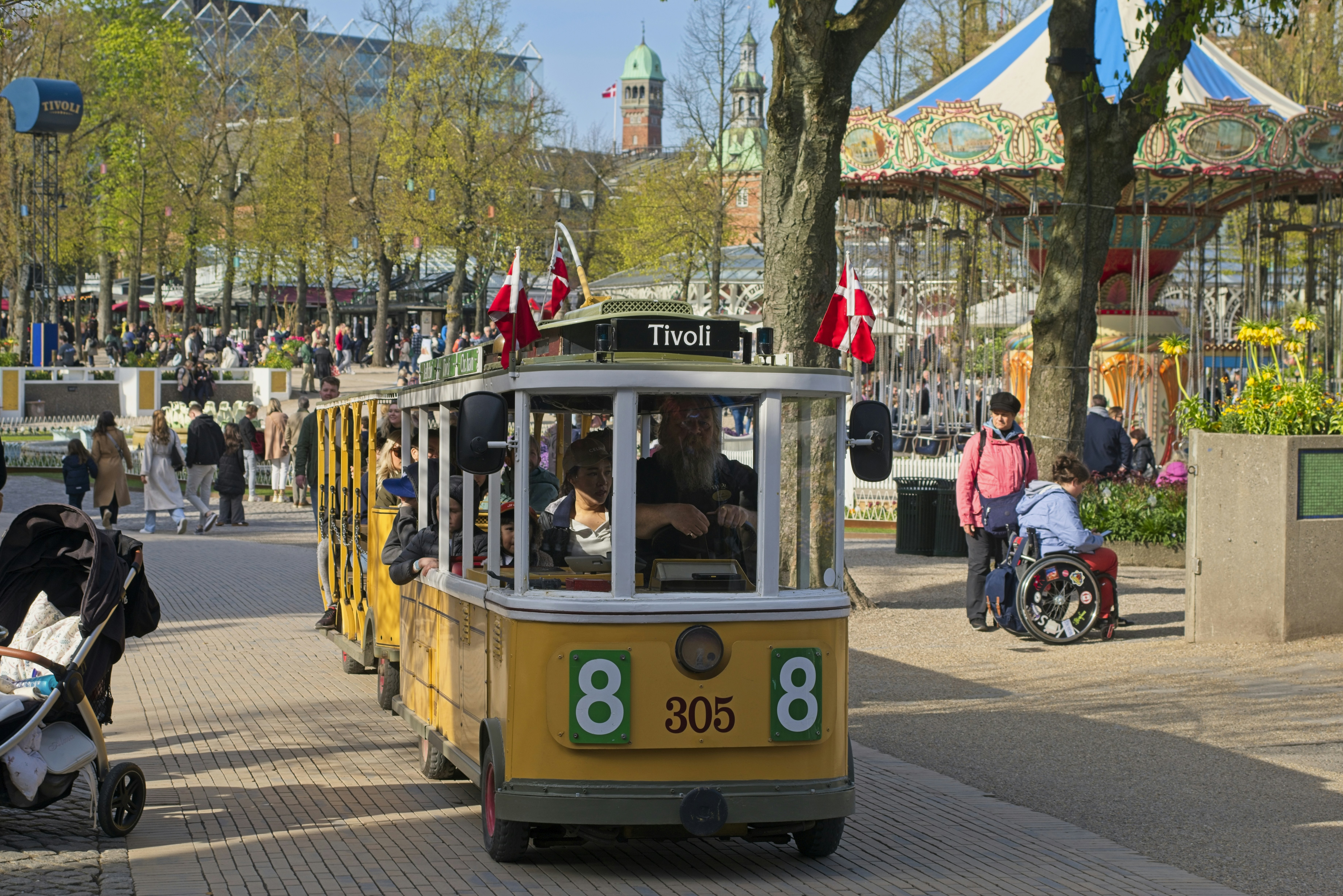 Yellow Tram Through a Busy City Park